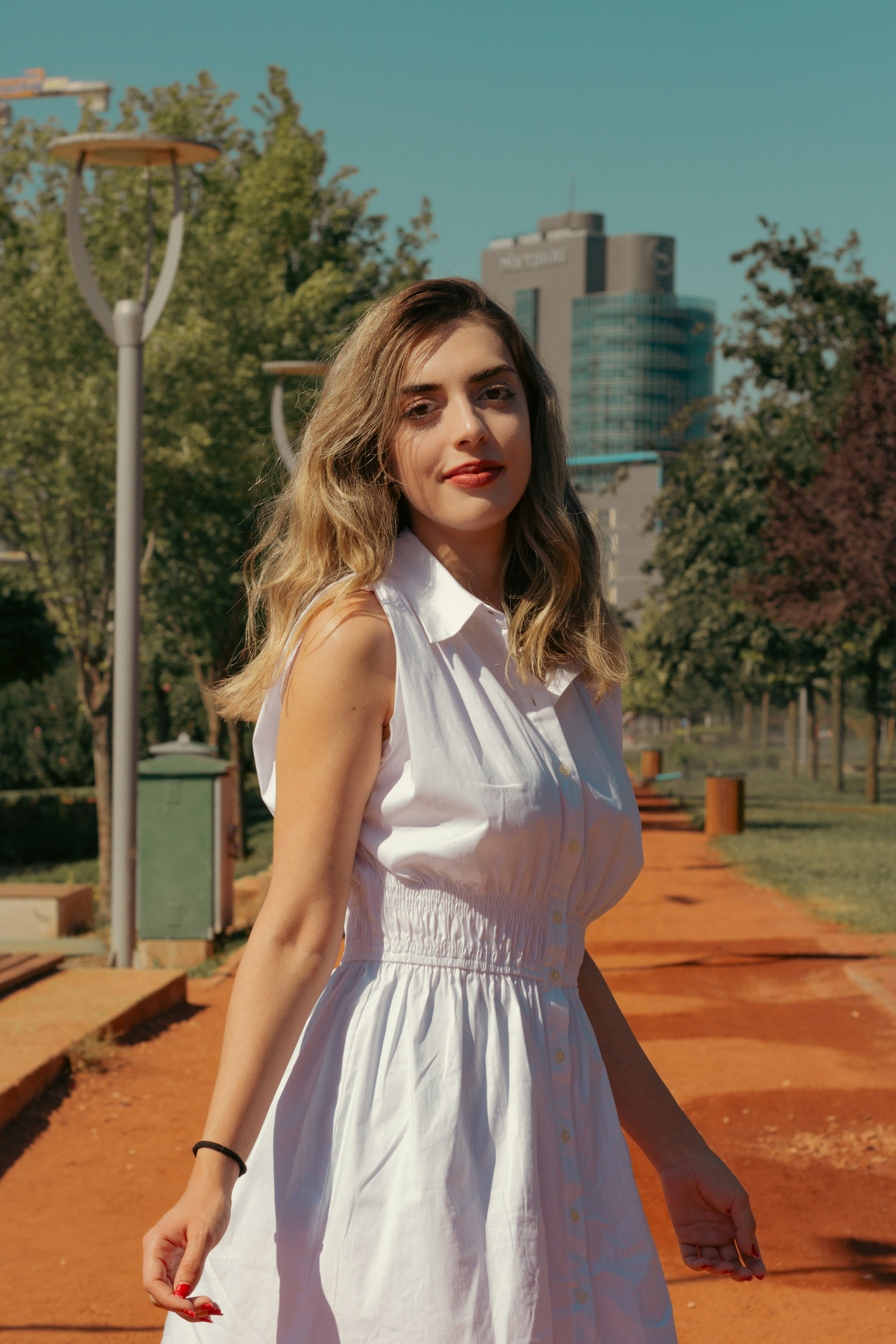 A woman in a white dress standing on a sidewalk photo – Free Portrait ...