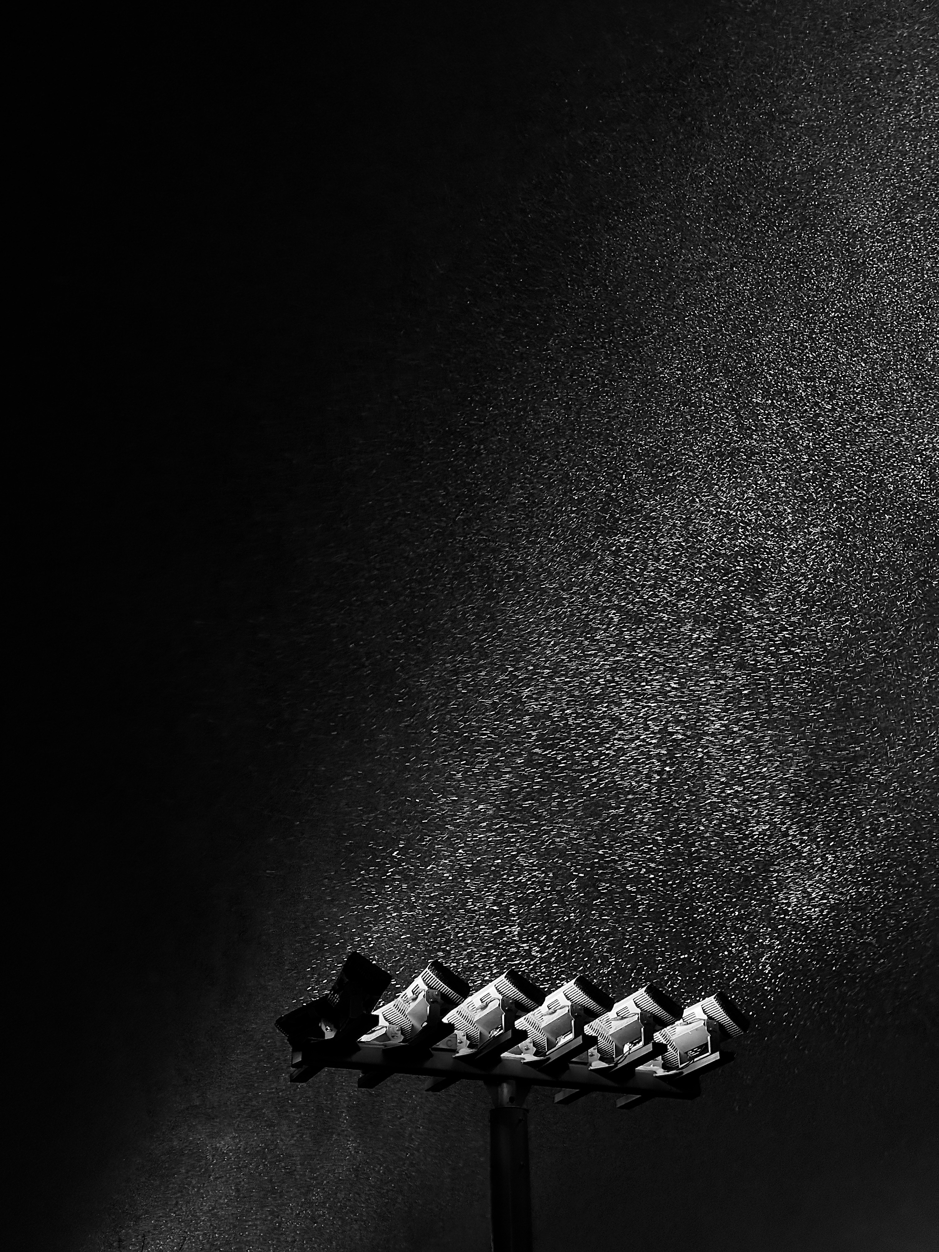 Monochrome beacon: floodlight array piercing a misty night