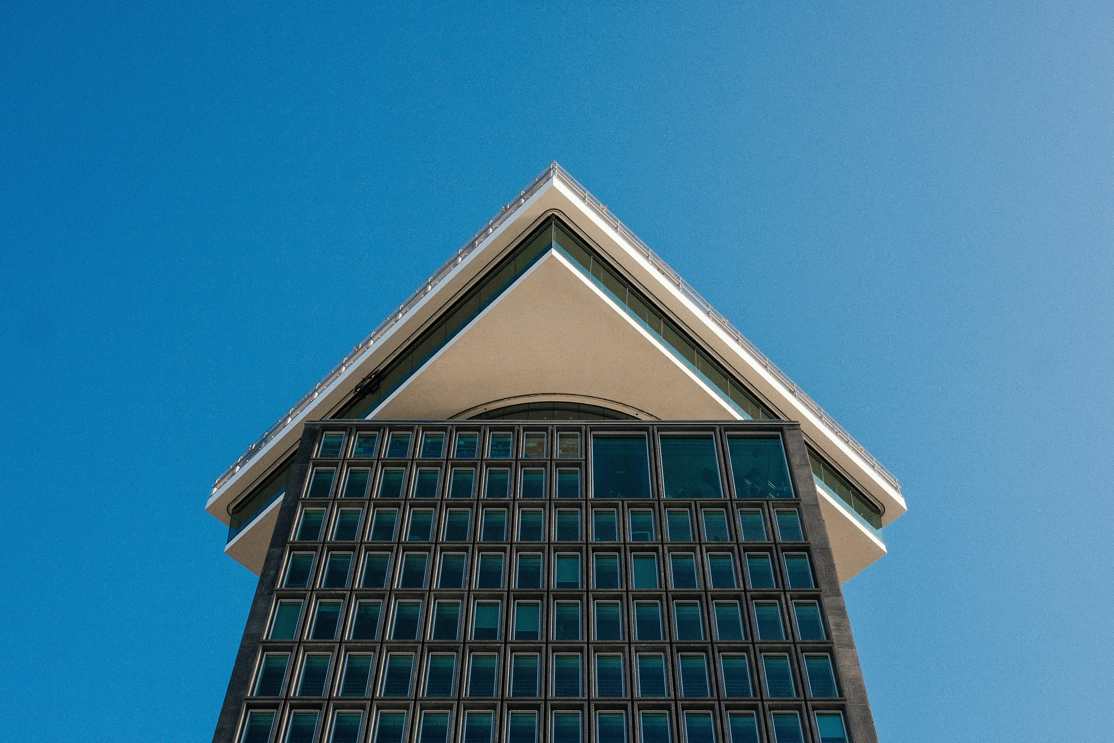 Modern building with a triangular roof against a clear blue sky.