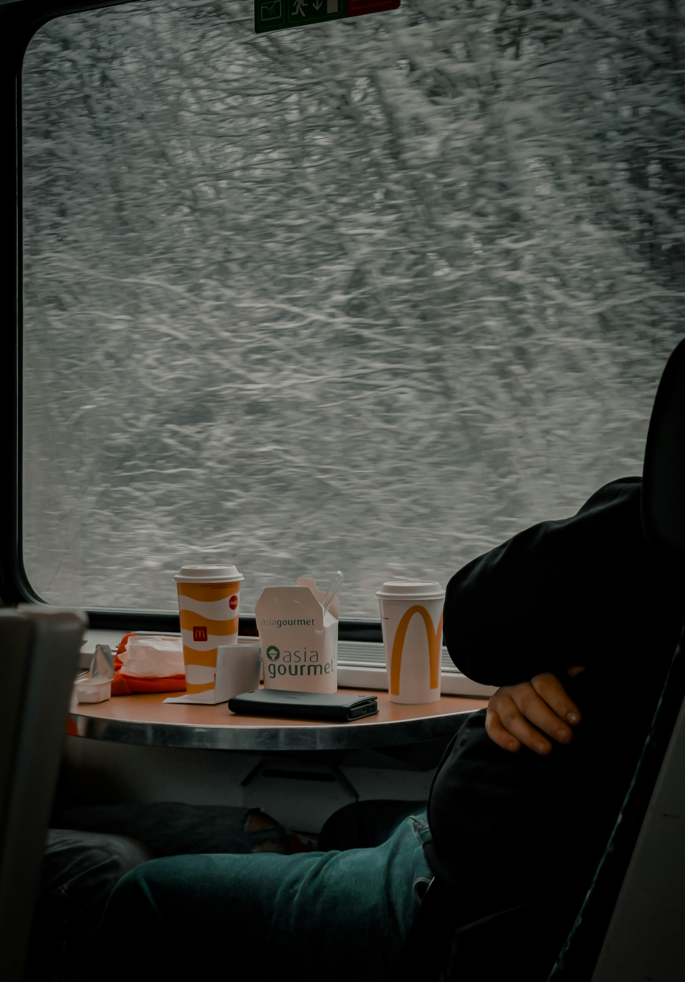 Window-side Pause: Coffee Cups, Takeout Bag, and a Smartphone on a Moving Train Table