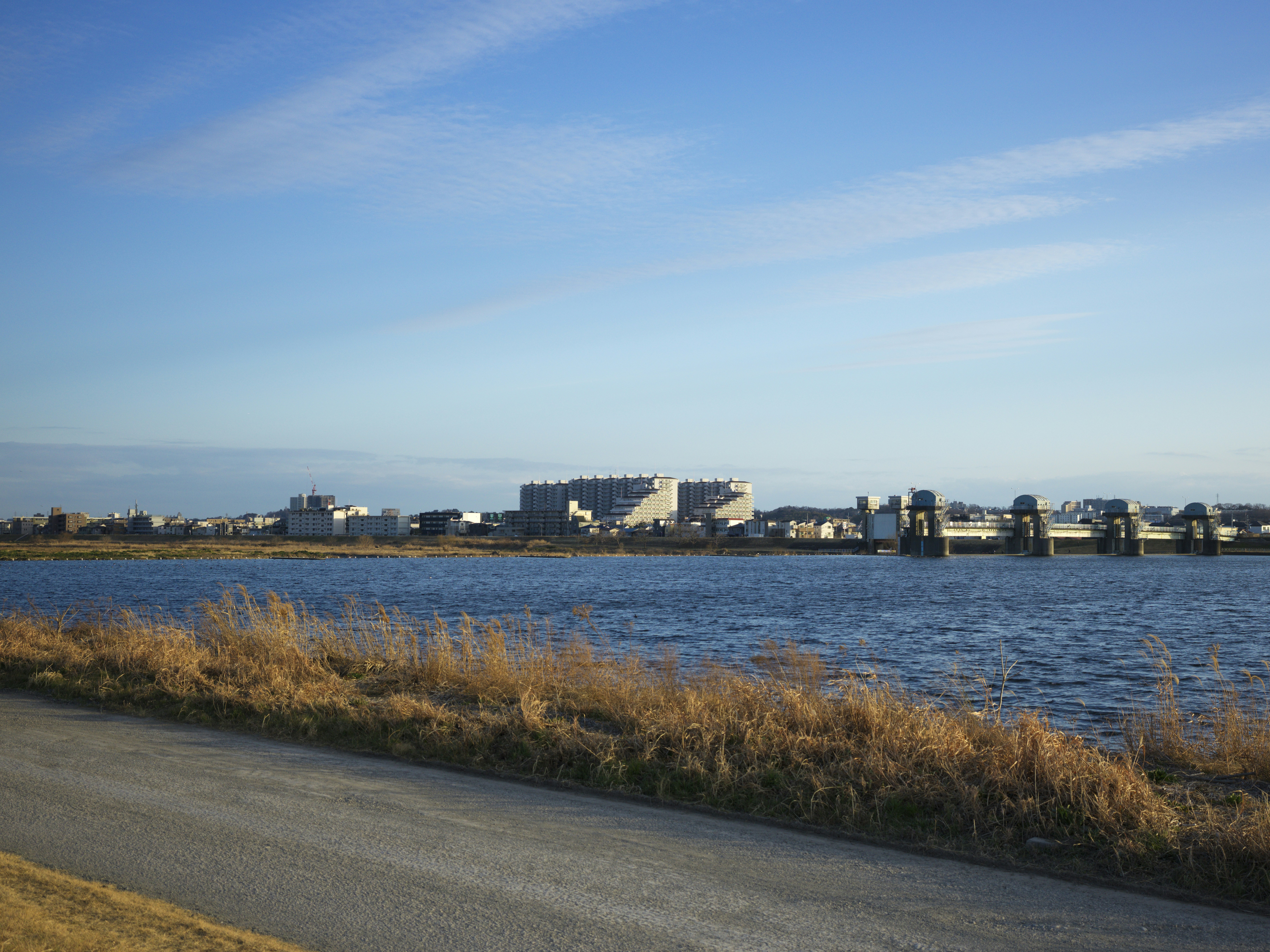 City skyline across a river with wispy clouds in a clear blue sky.