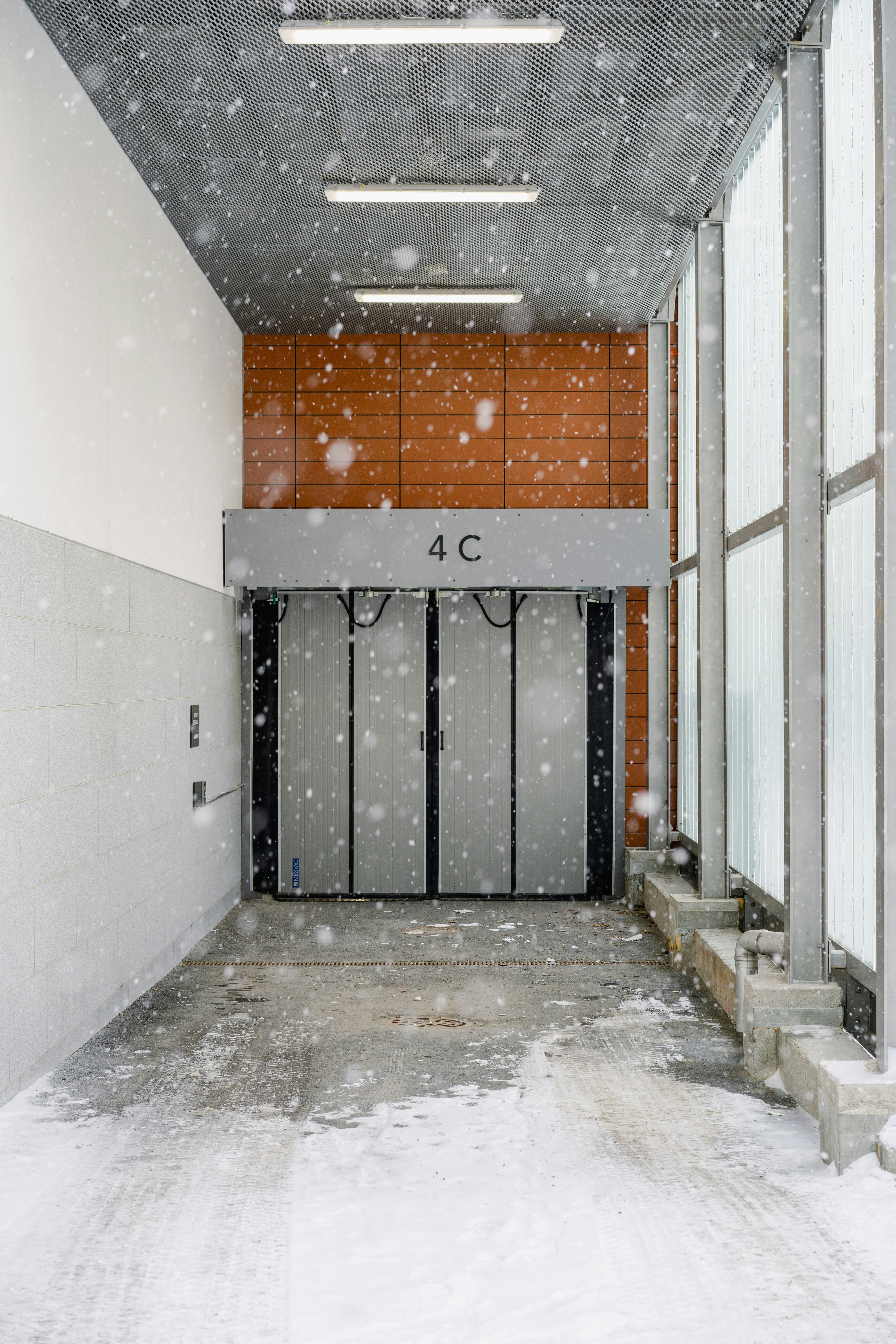 4C Gateway in Falling Snow: A Quiet Corridor Framed by Glass and Orange Panels