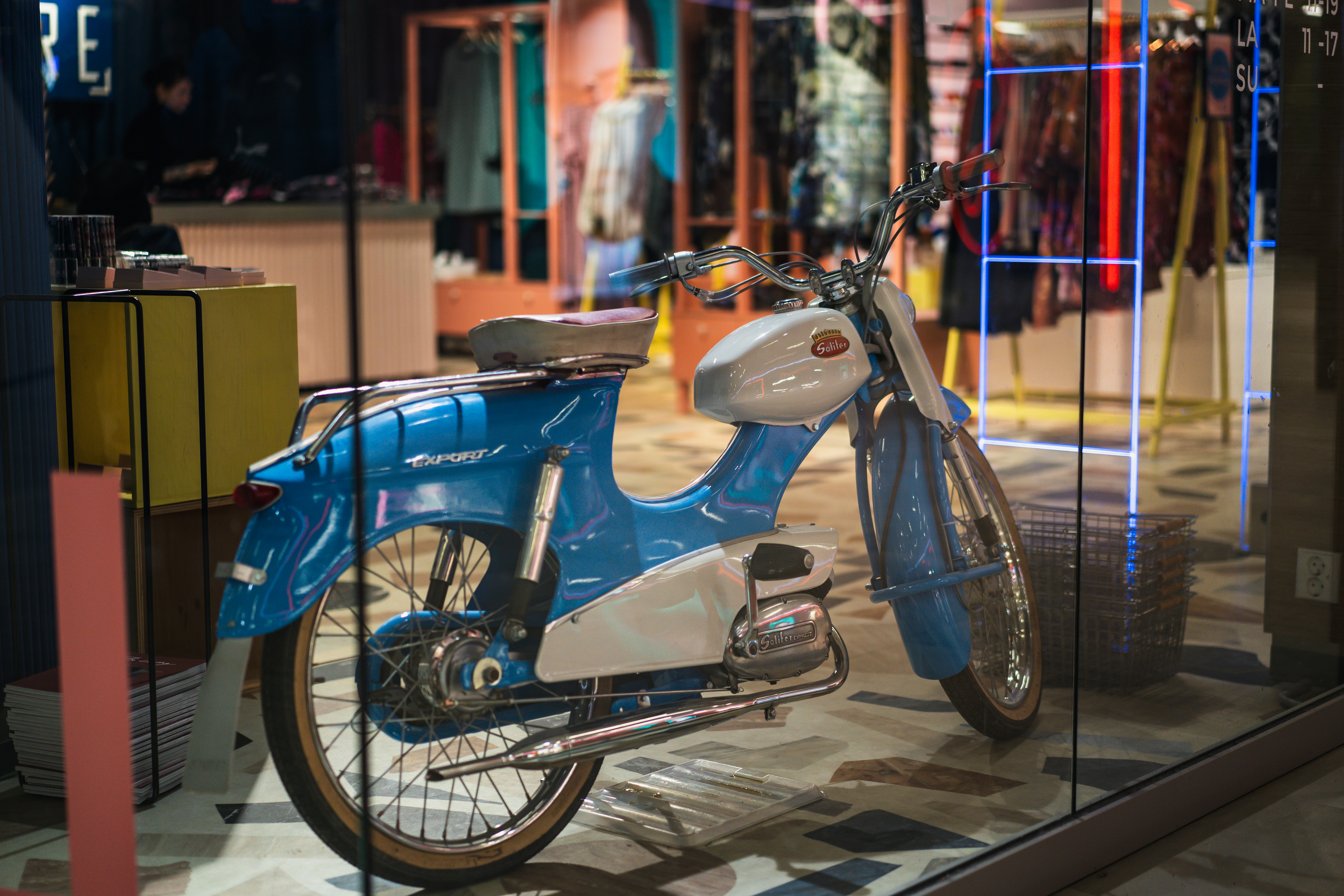 Neon-lit Blue Vintage Scooter in a Fashion Store Window