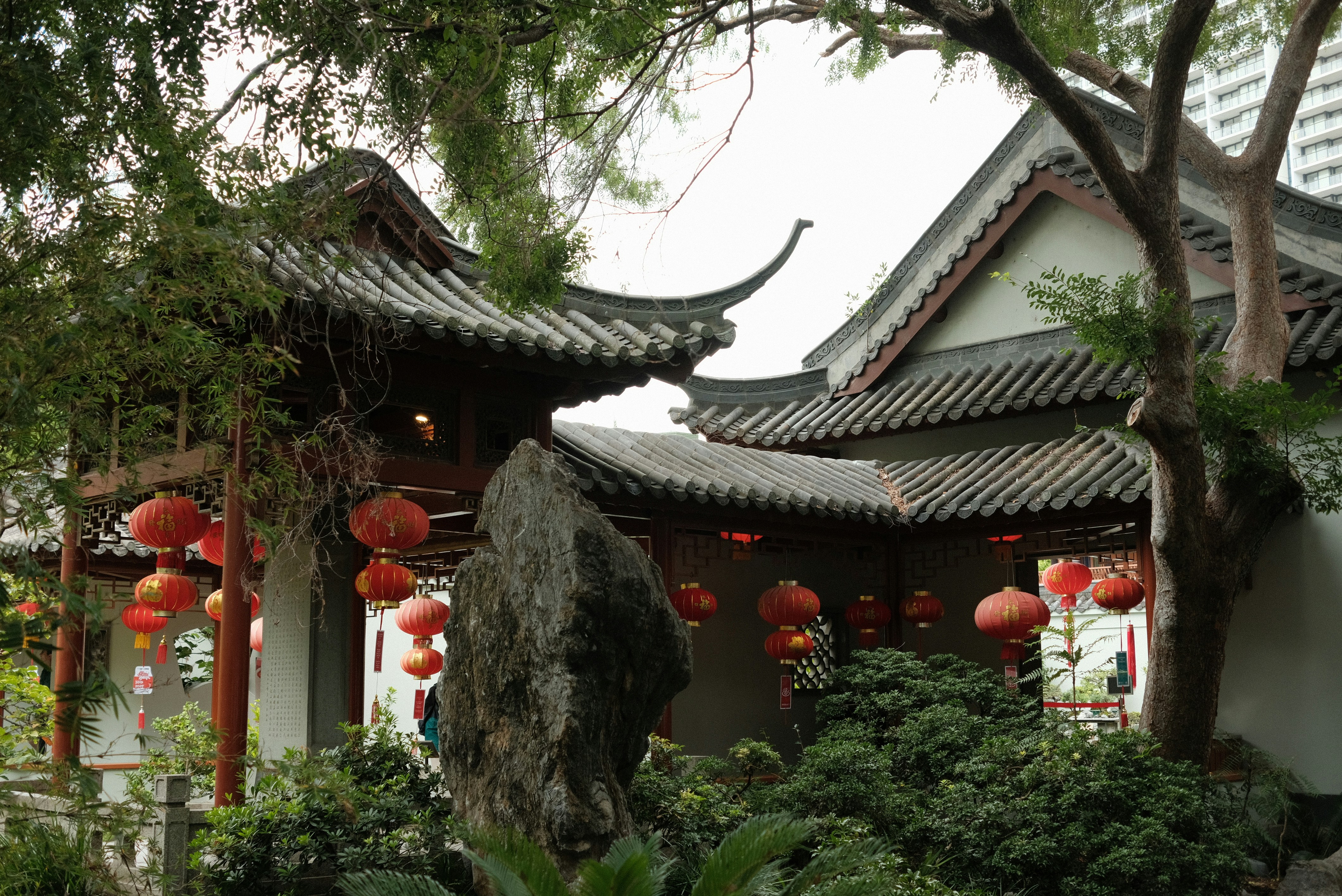 Traditional Chinese architecture adorned with red lanterns surrounded by lush greenery.