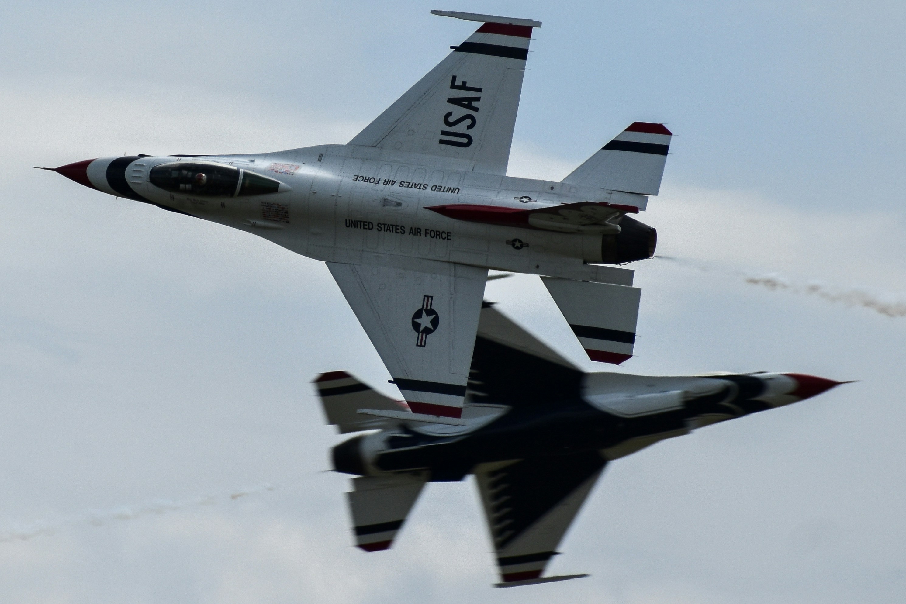 United States Air Force F-16 Thunderbirds | A fighter jet flying through a cloudy blue sky