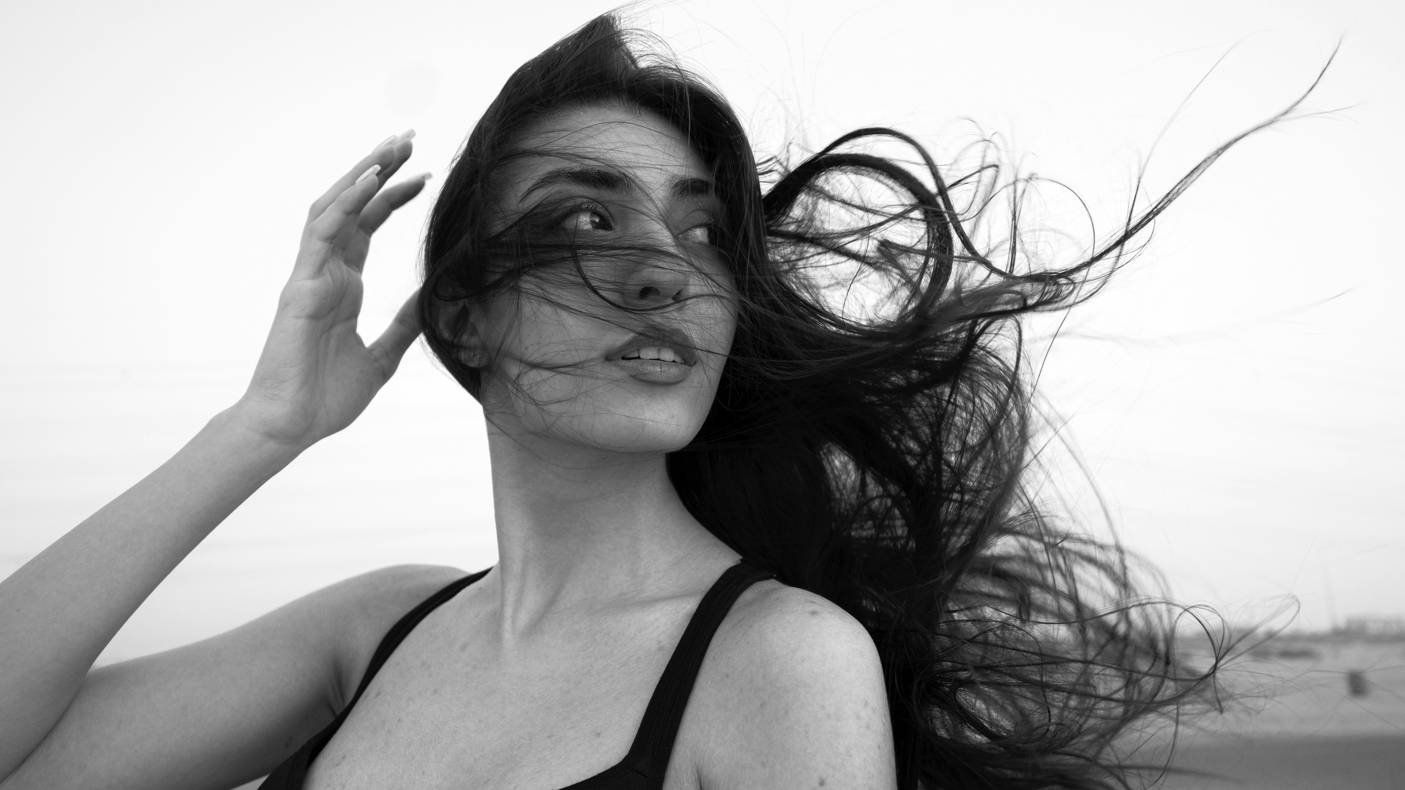 Woman with flowing hair gazing into the distance against a soft backdrop.
