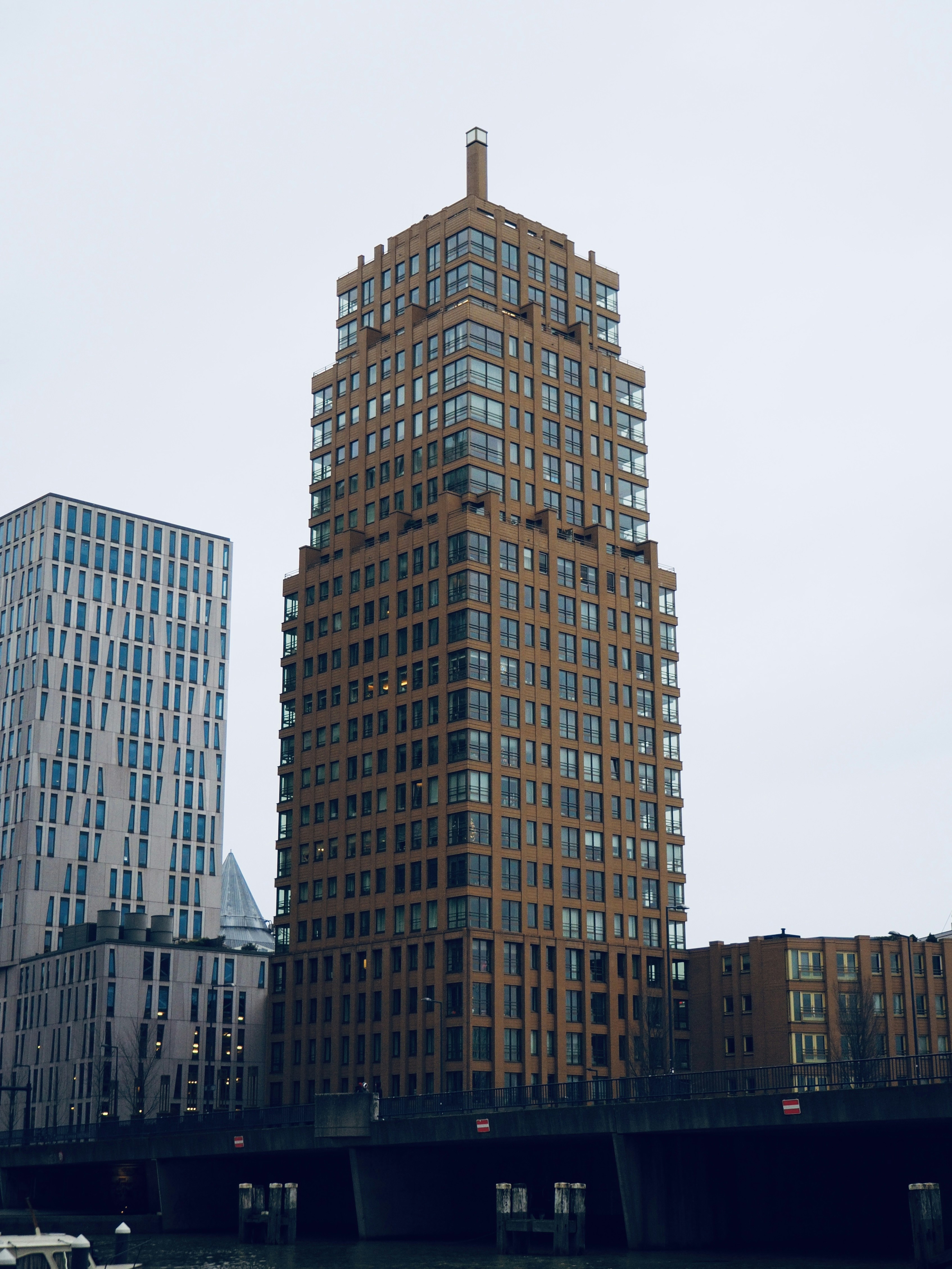 A very tall building sitting next to a river photo – Free City Image on ...