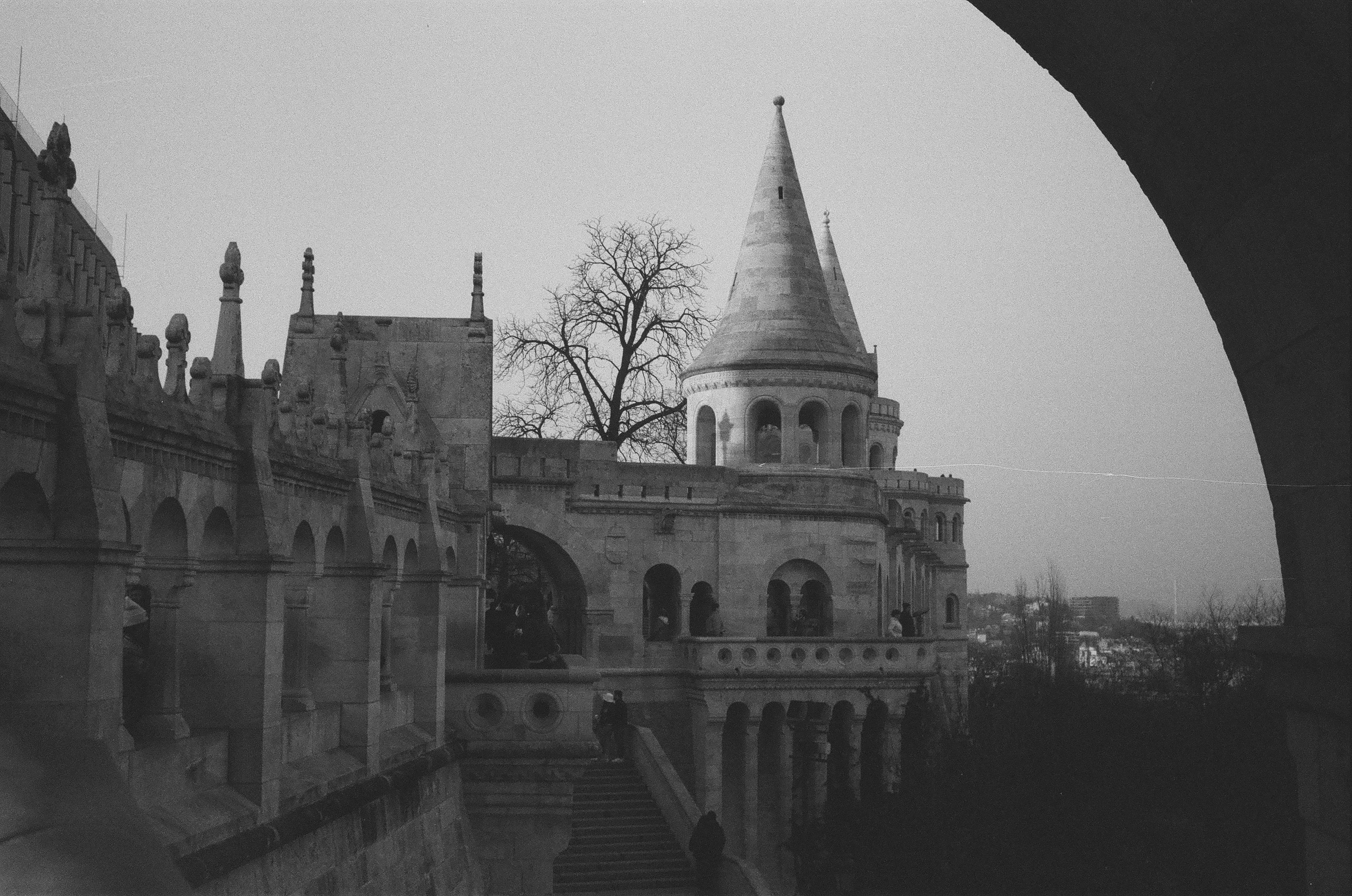 Black-and-white photograph of a fortress terrace with arched colonnades and a central conical turret overlooking the Danube valley.