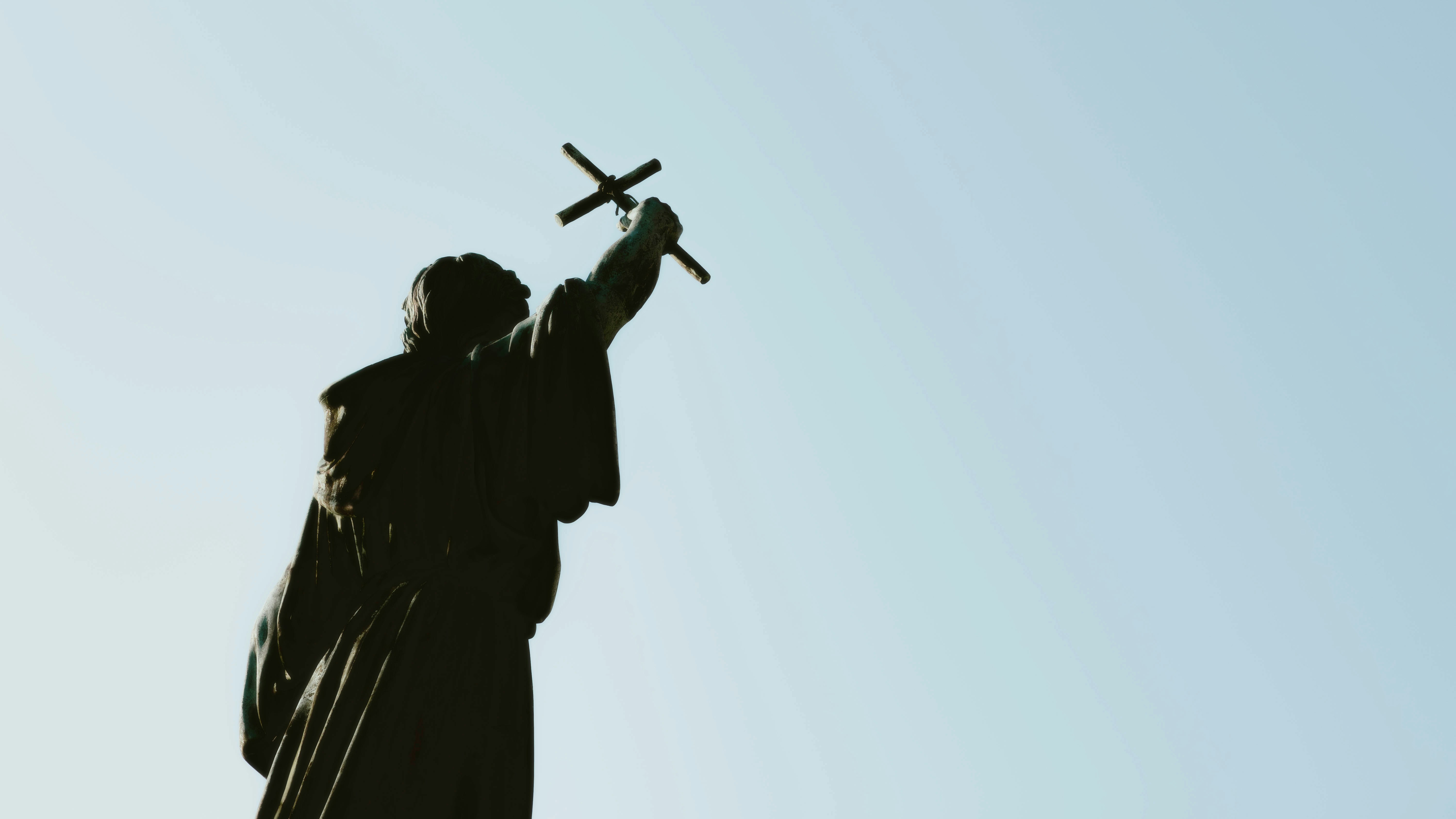 A statue of a man holding a cross on top of a building photo – Free ...