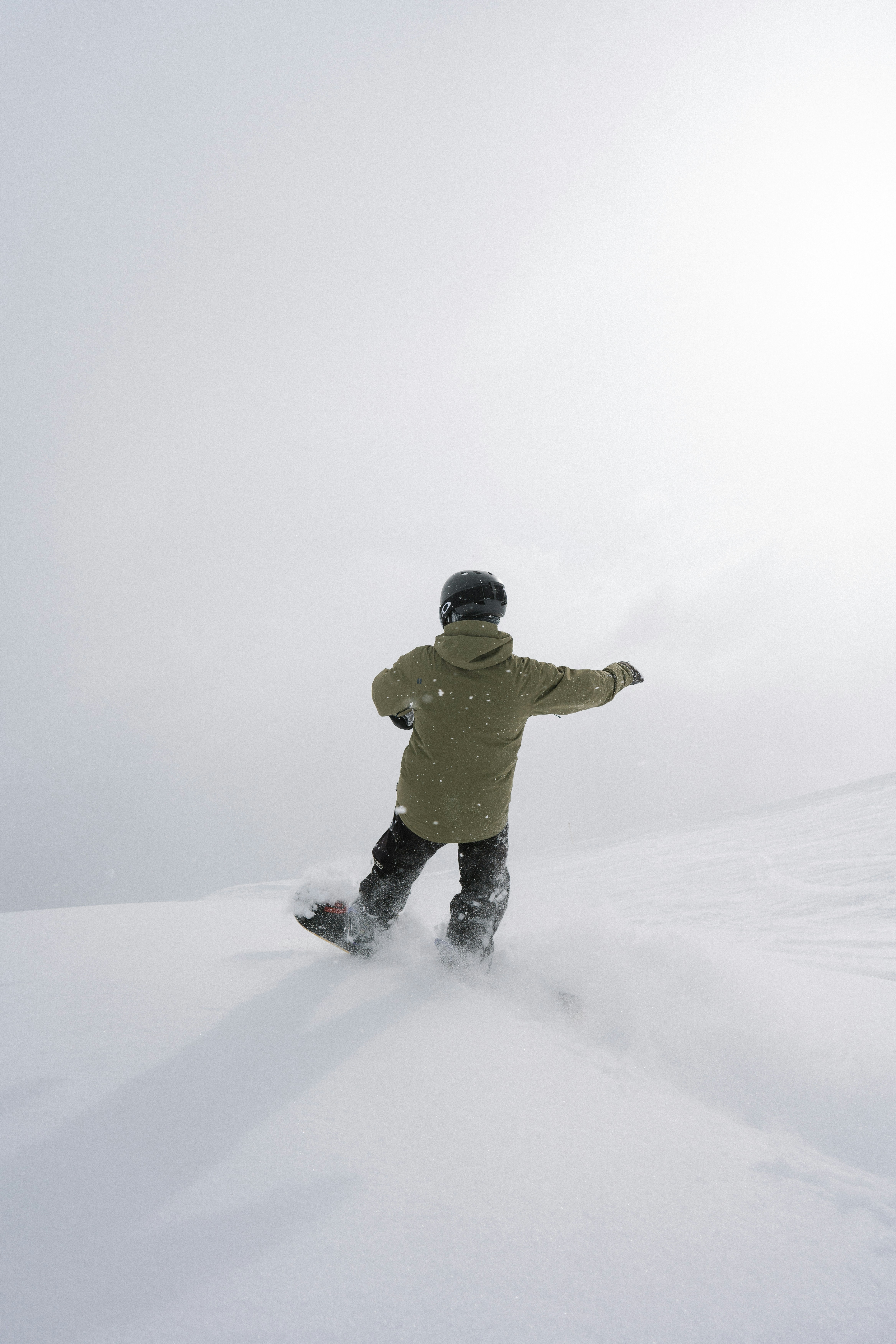 A person riding a snowboard down a snow covered slope photo – Free ...