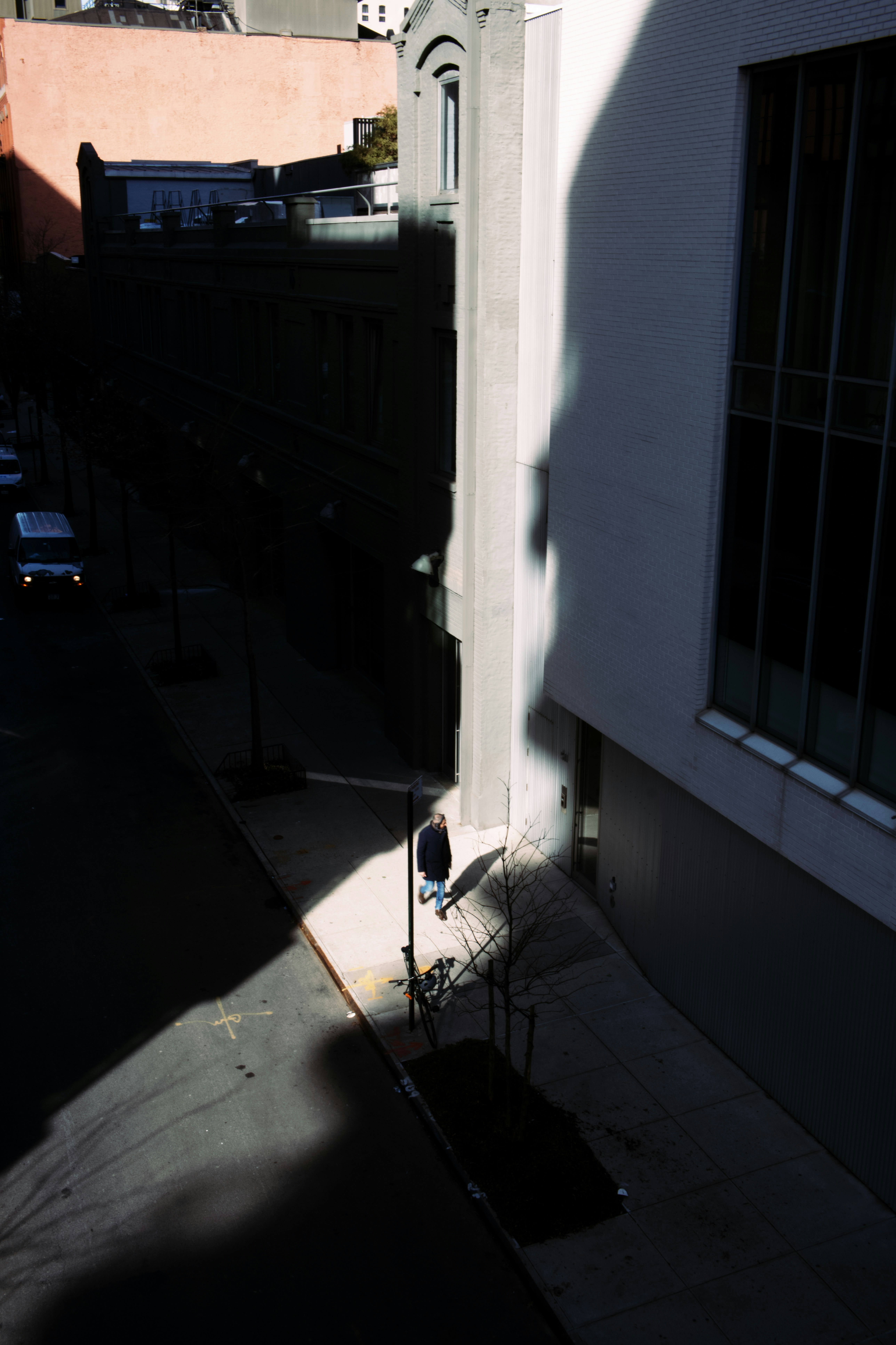 Sunlit Pedestrian at the Edge of the Concrete Canyon