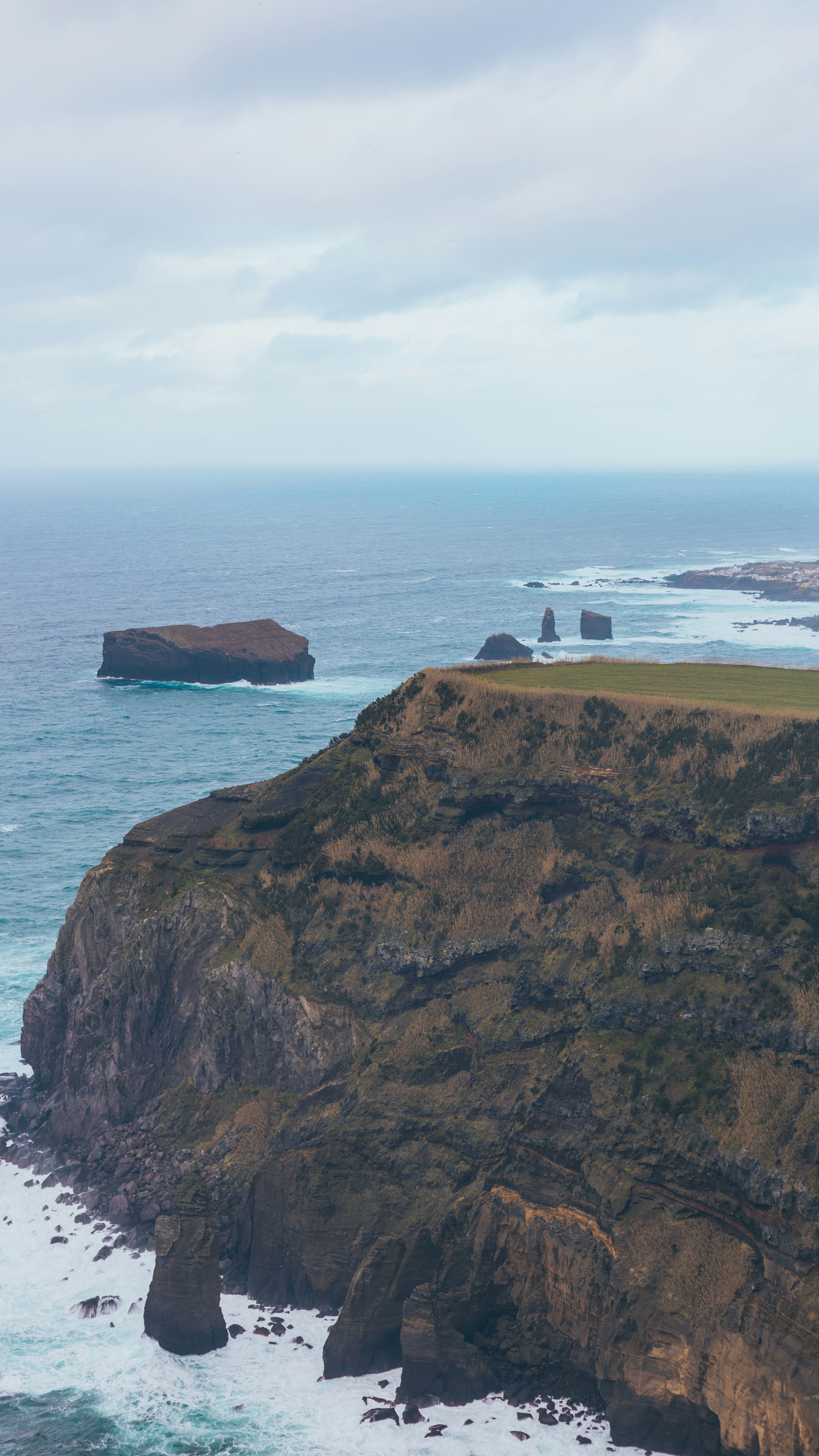 A lighthouse on a rocky cliff overlooking the ocean photo – Free ...