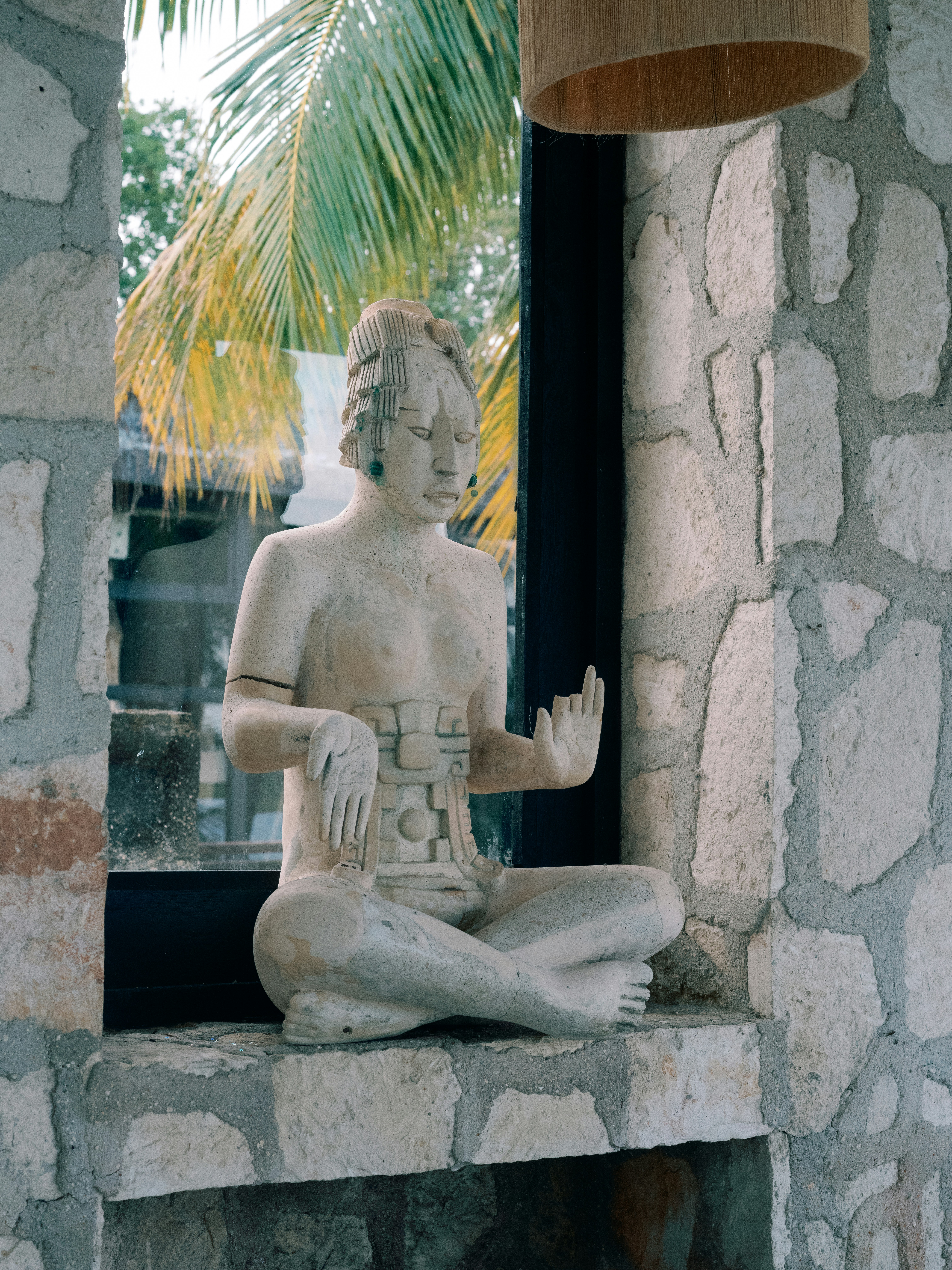 Meditative Buddha on a Stone Ledge, Framed by Palm Light
