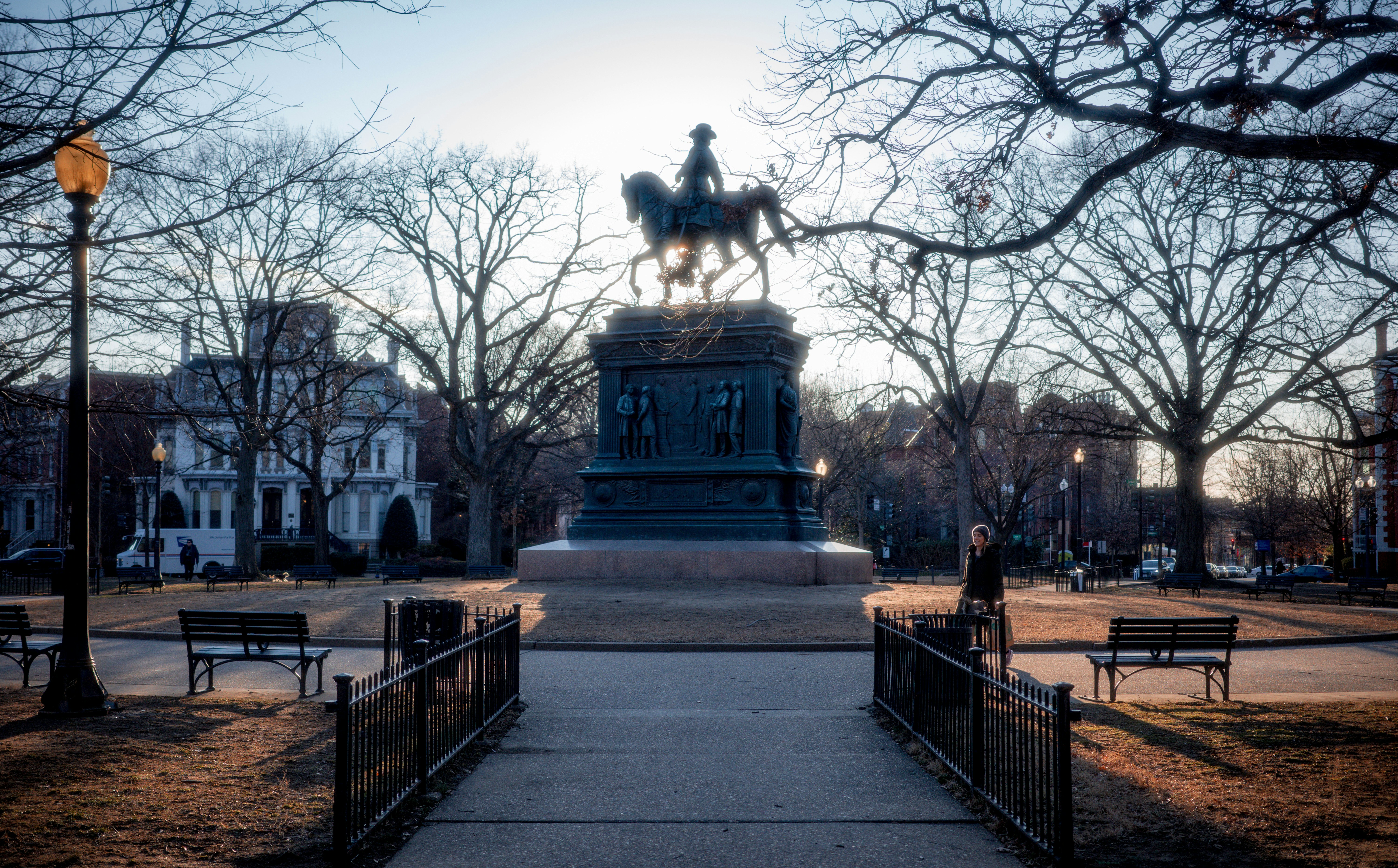 Equestrian statue in a park under a clear morning sky with bare trees and soft sunlight.