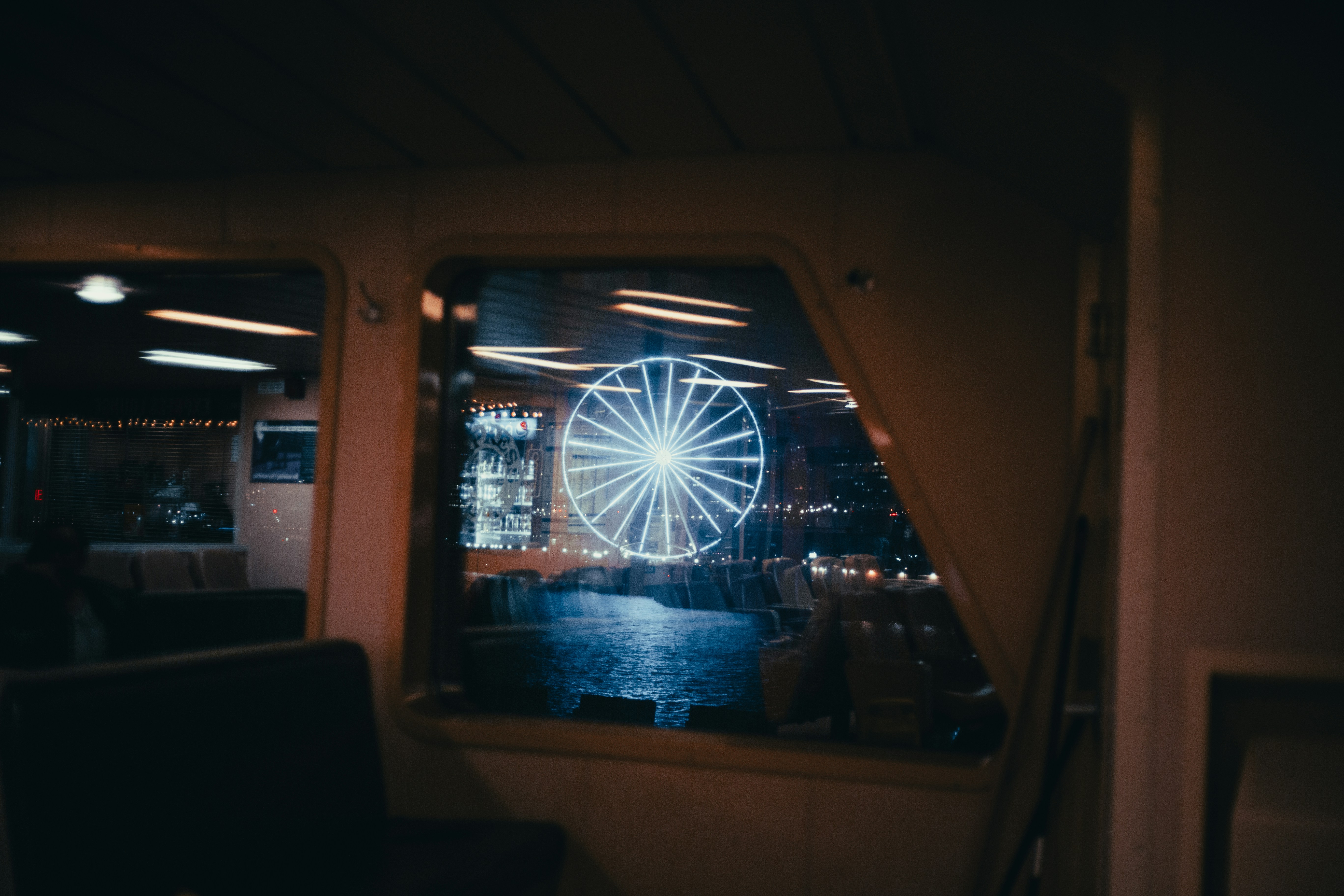 Blue Neon Ferris Wheel Through a Cabin Window at Night