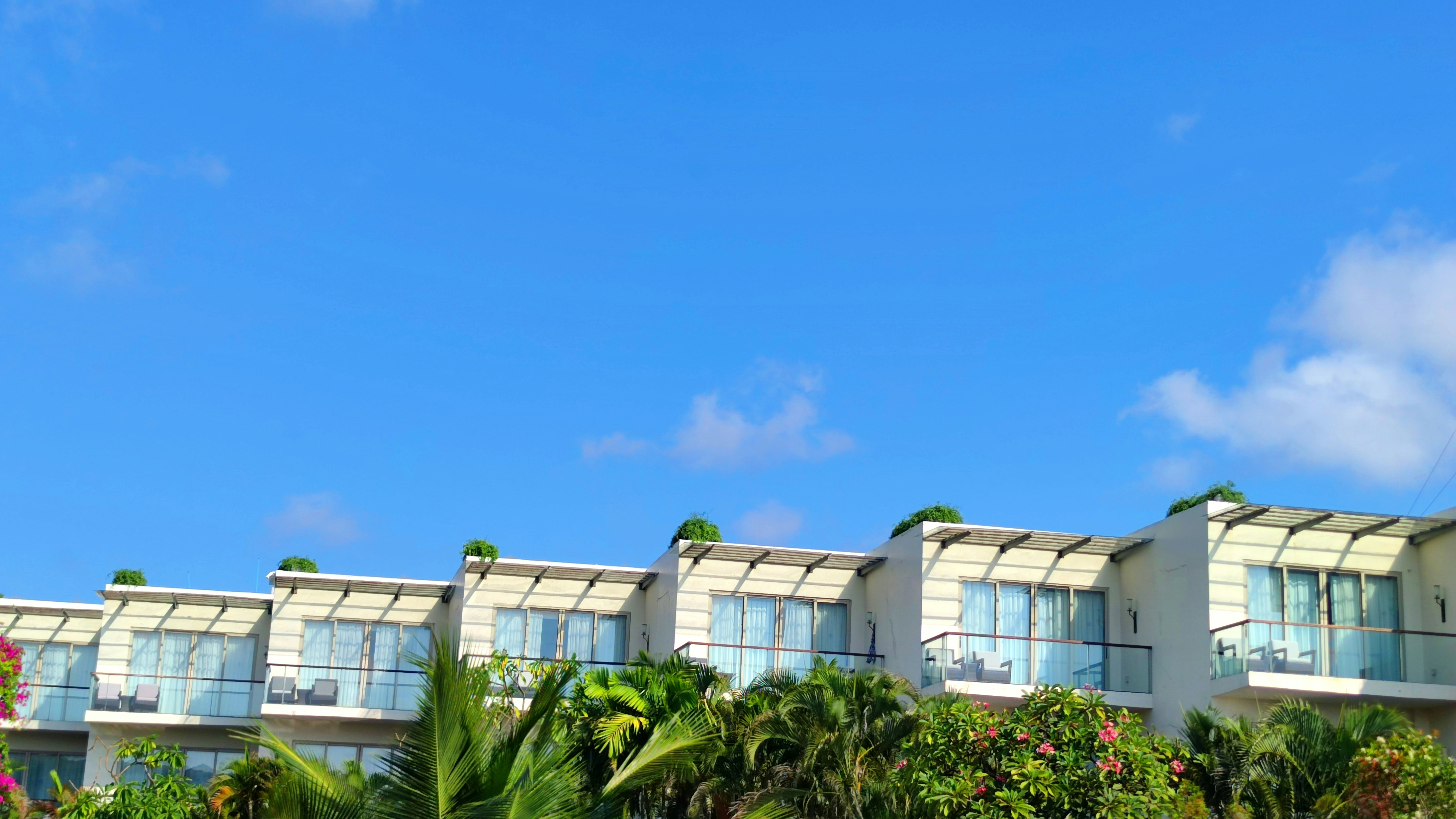 Modern resort facade with lush greenery under a clear blue sky.