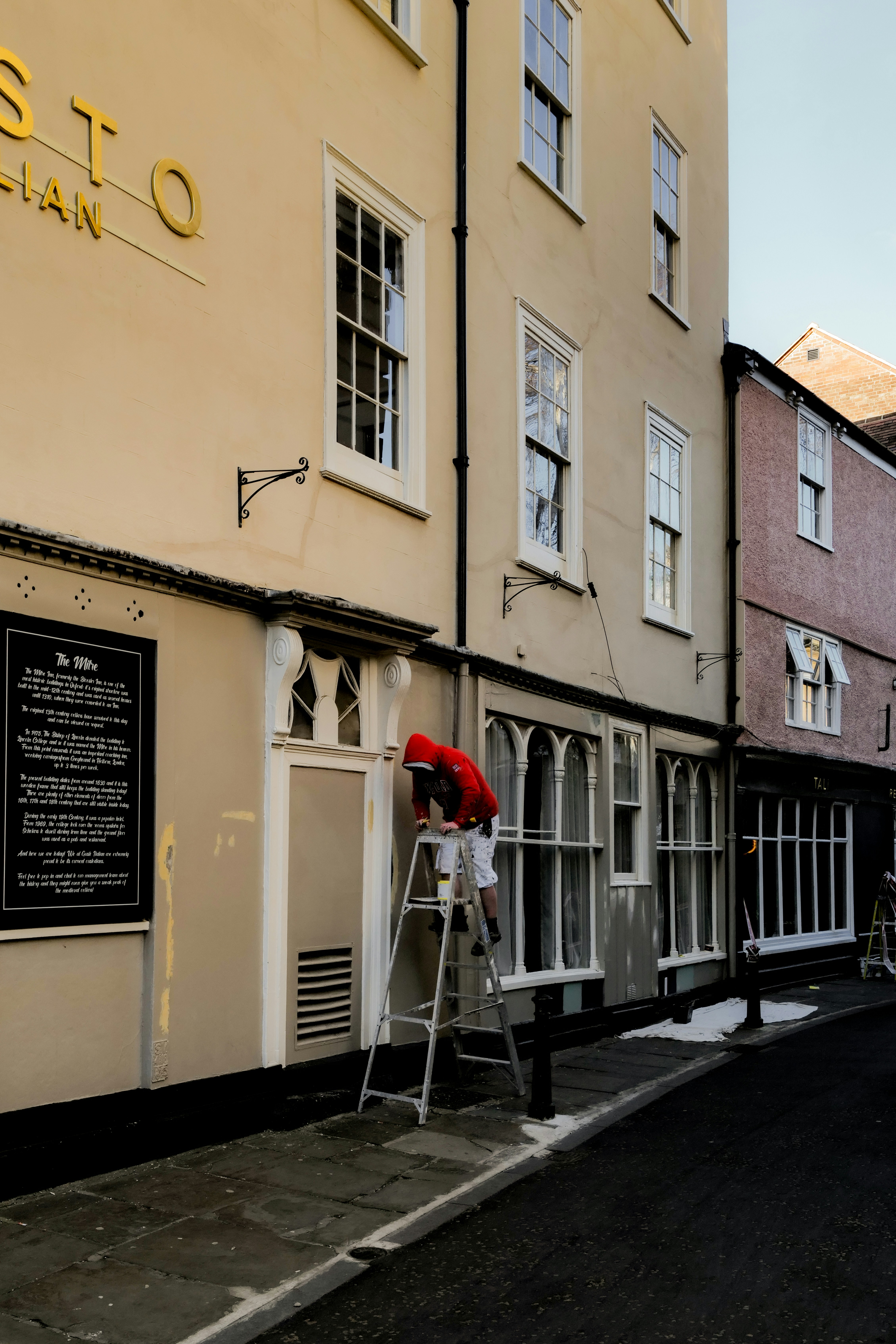 Red-Hooded Helper on a Narrow London Street