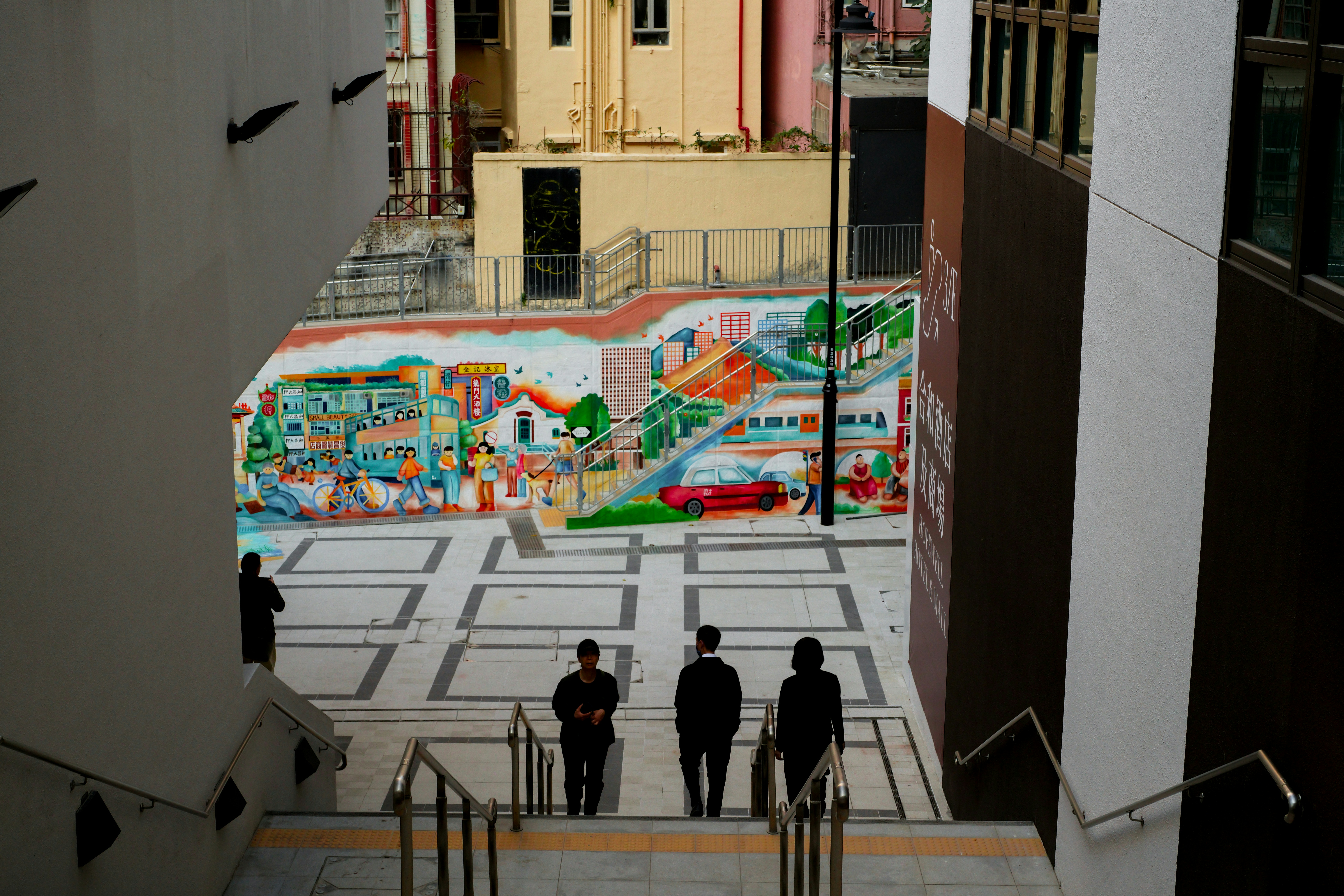 Vibrant mural depicting urban life viewed from descending stairs with silhouetted figures.