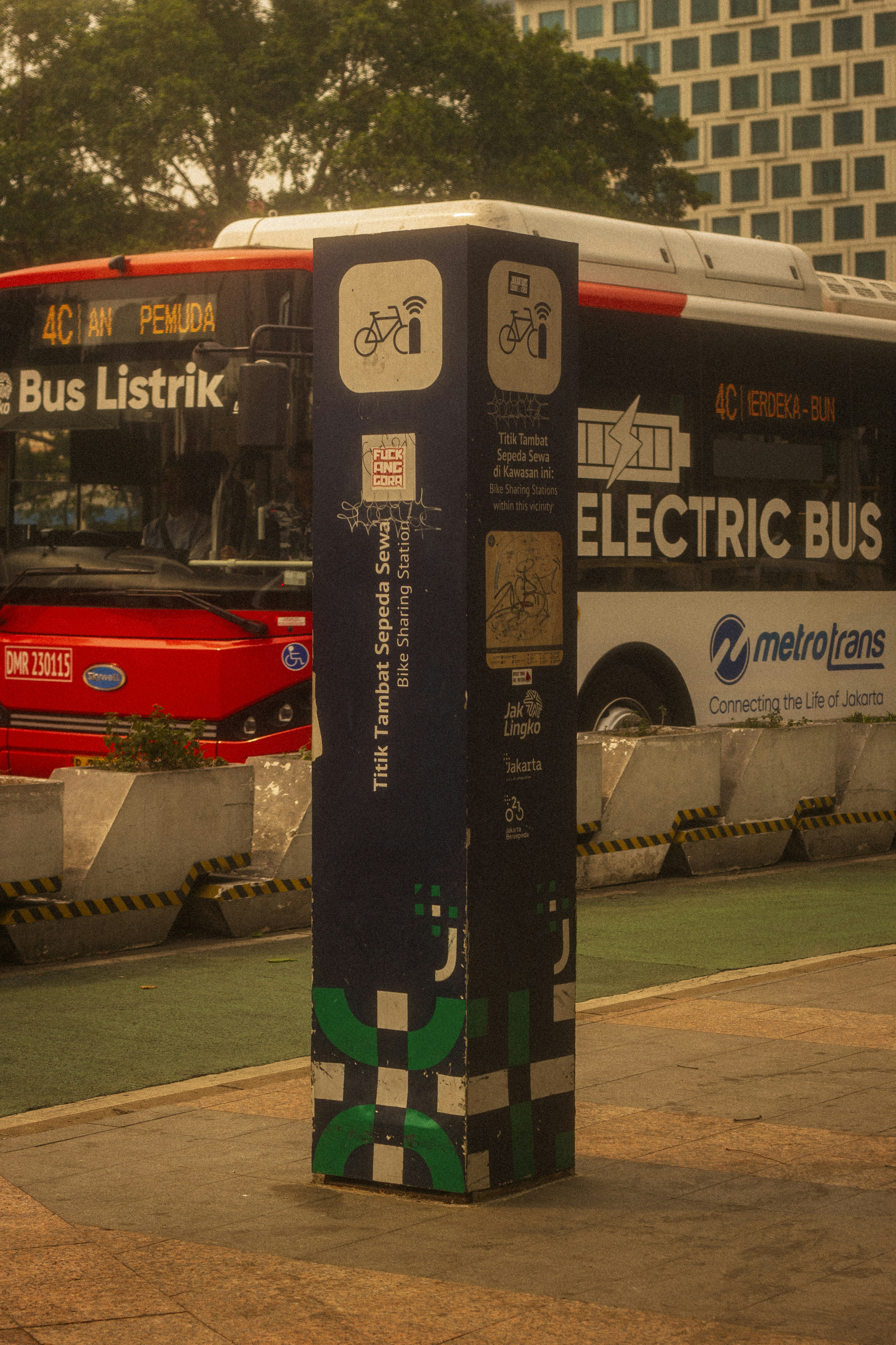 Pole of Signage at Jakarta Electric Bus Stop, Framed by a Red-Blue Fleet