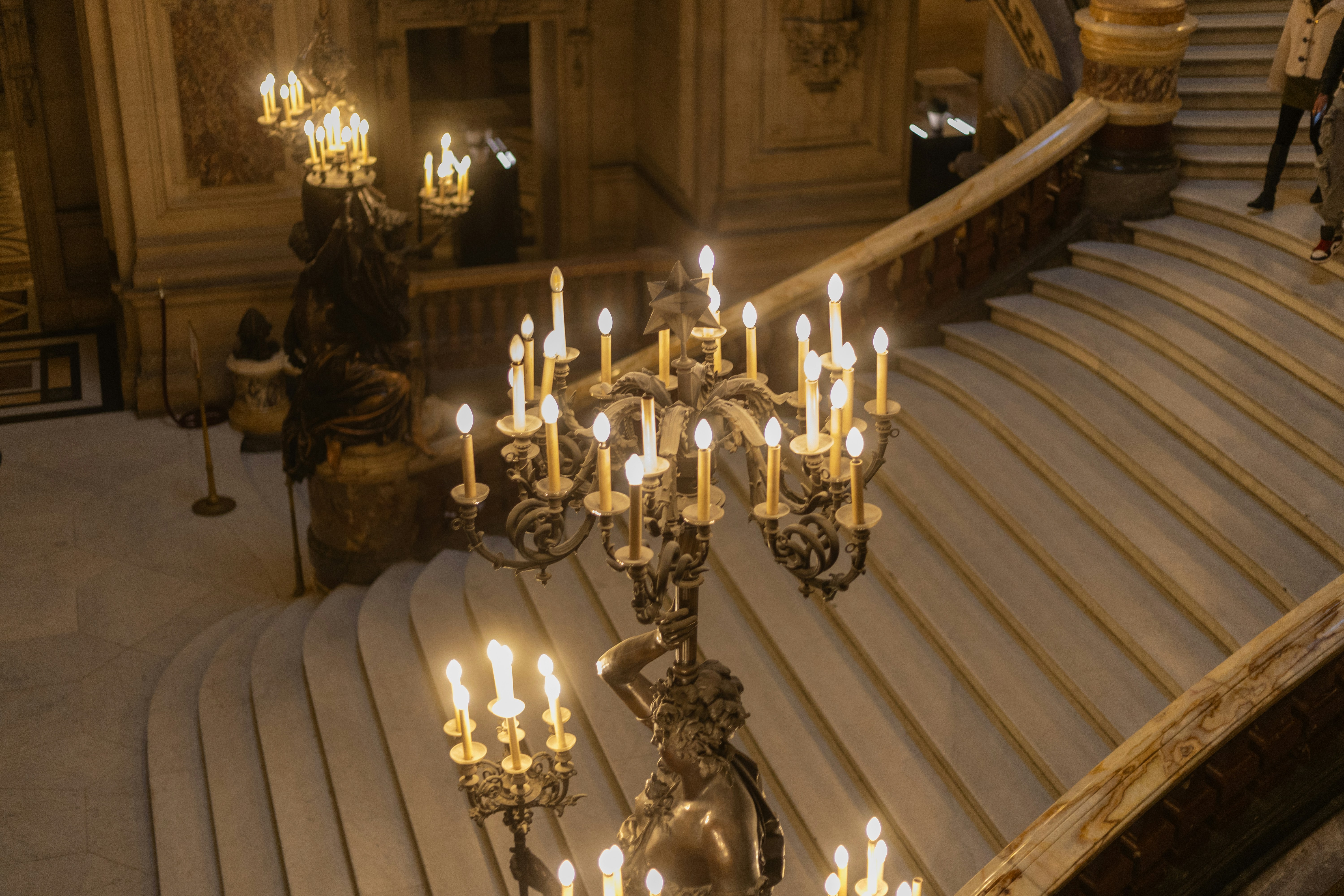 Candlelit Spiral: Opulent Marble Staircase Beneath Bronze Chandeliers