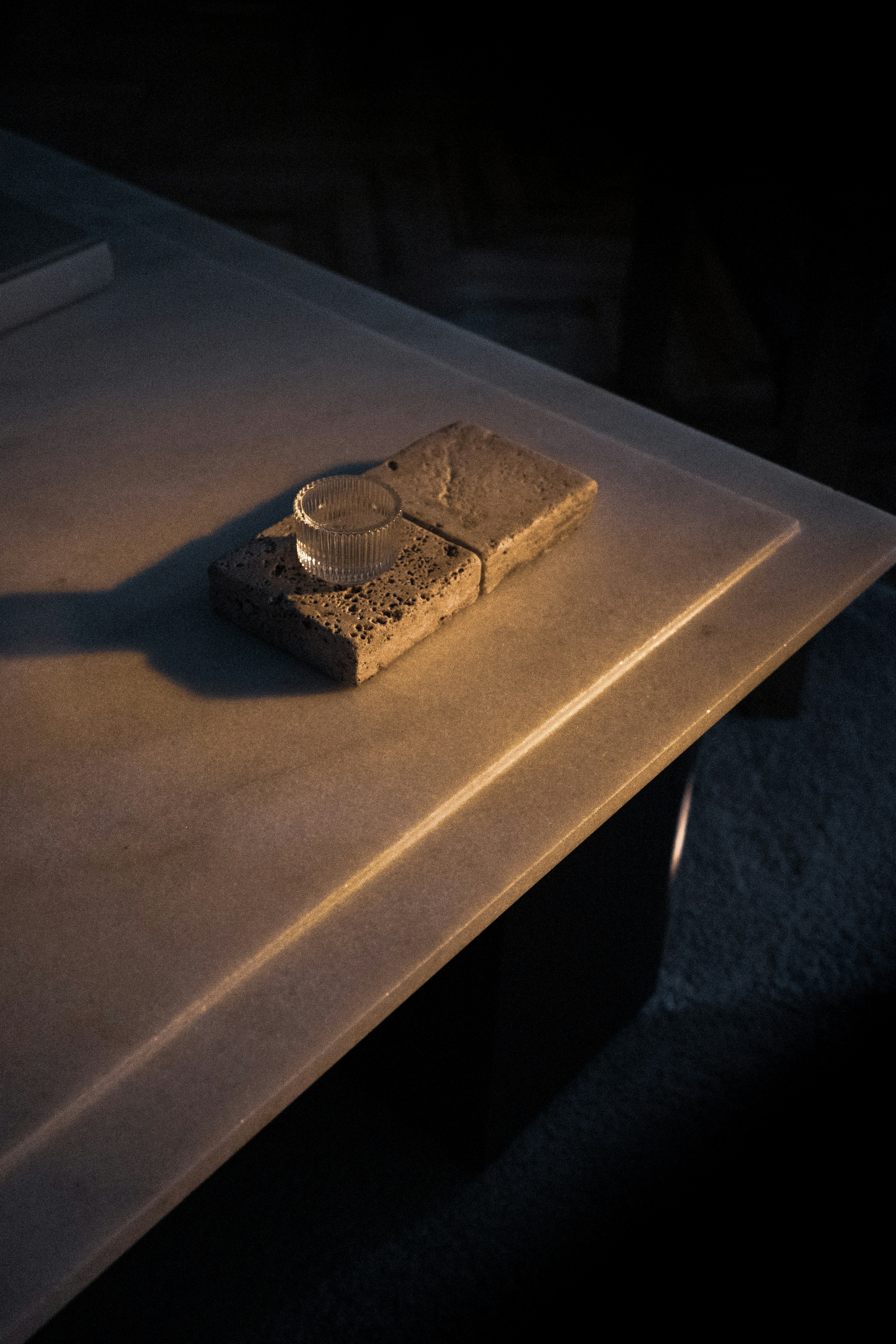 Amber Glow Still Life: Concrete Block with a Circular Dial on a Gleaming Table