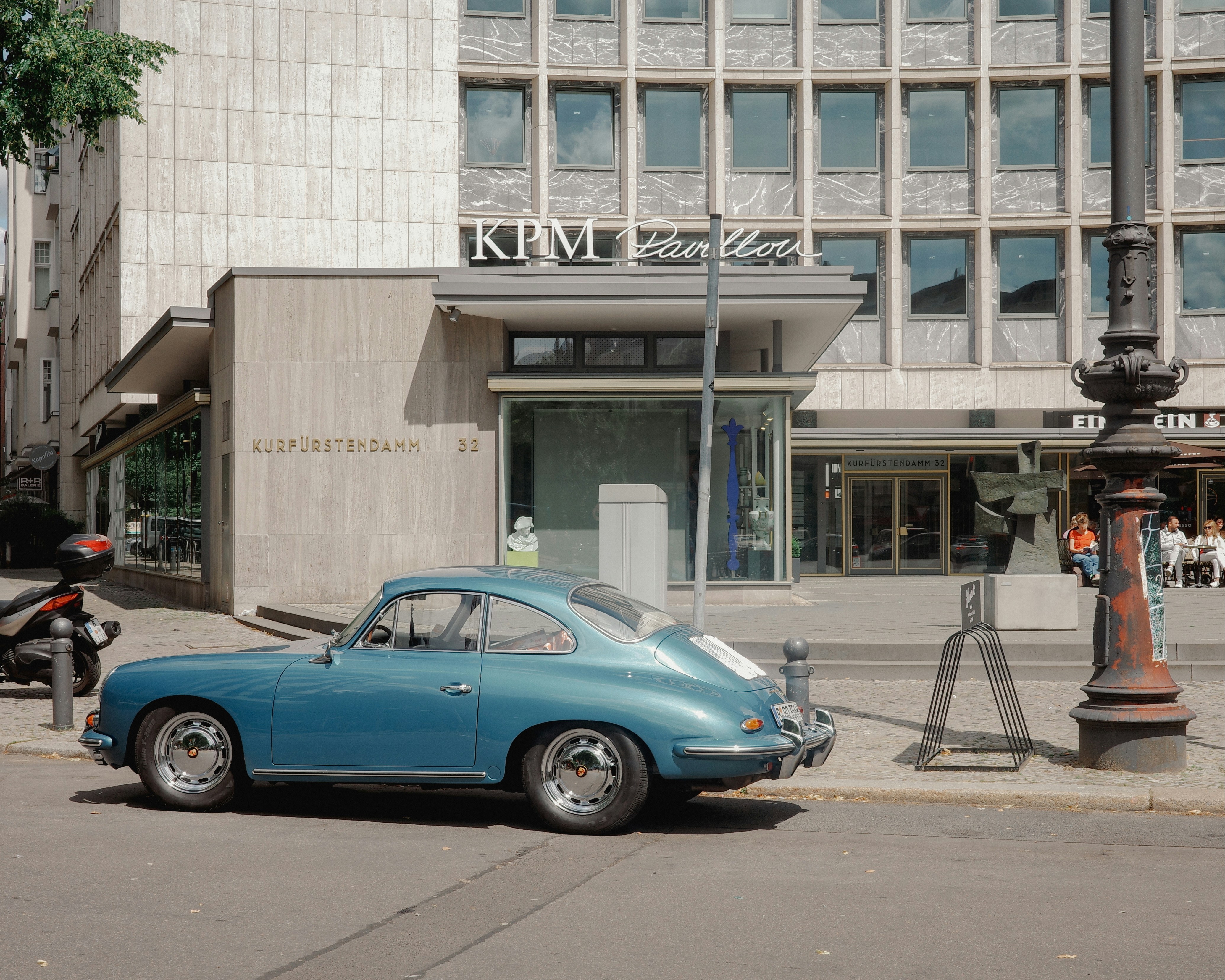 Azure Vintage Coupe Pauses at the Edge of a Modern Street