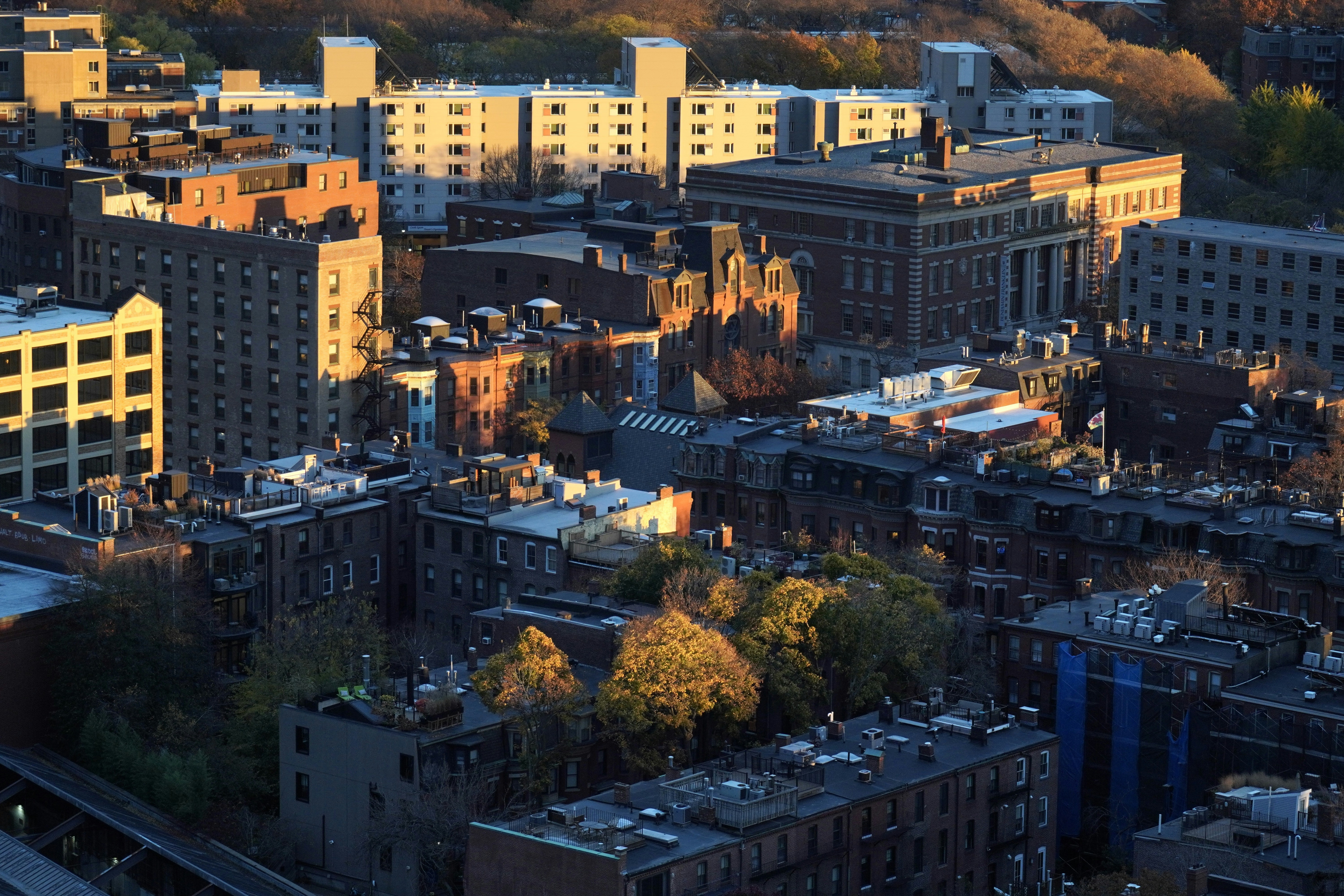 Boston's Back Bay at sunset with historic brownstones and autumn trees in warm golden light.