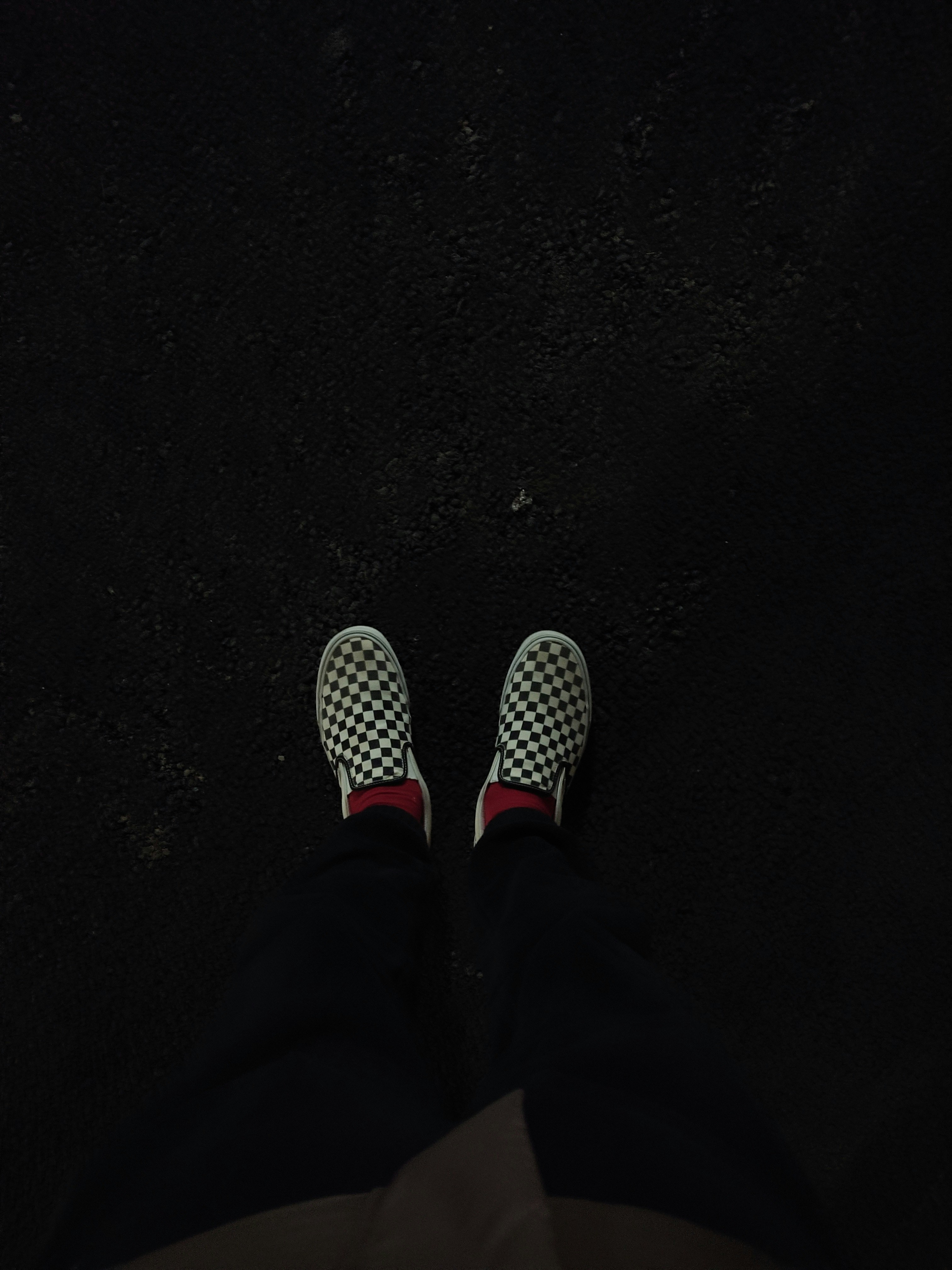 A person standing in the dark with their feet up