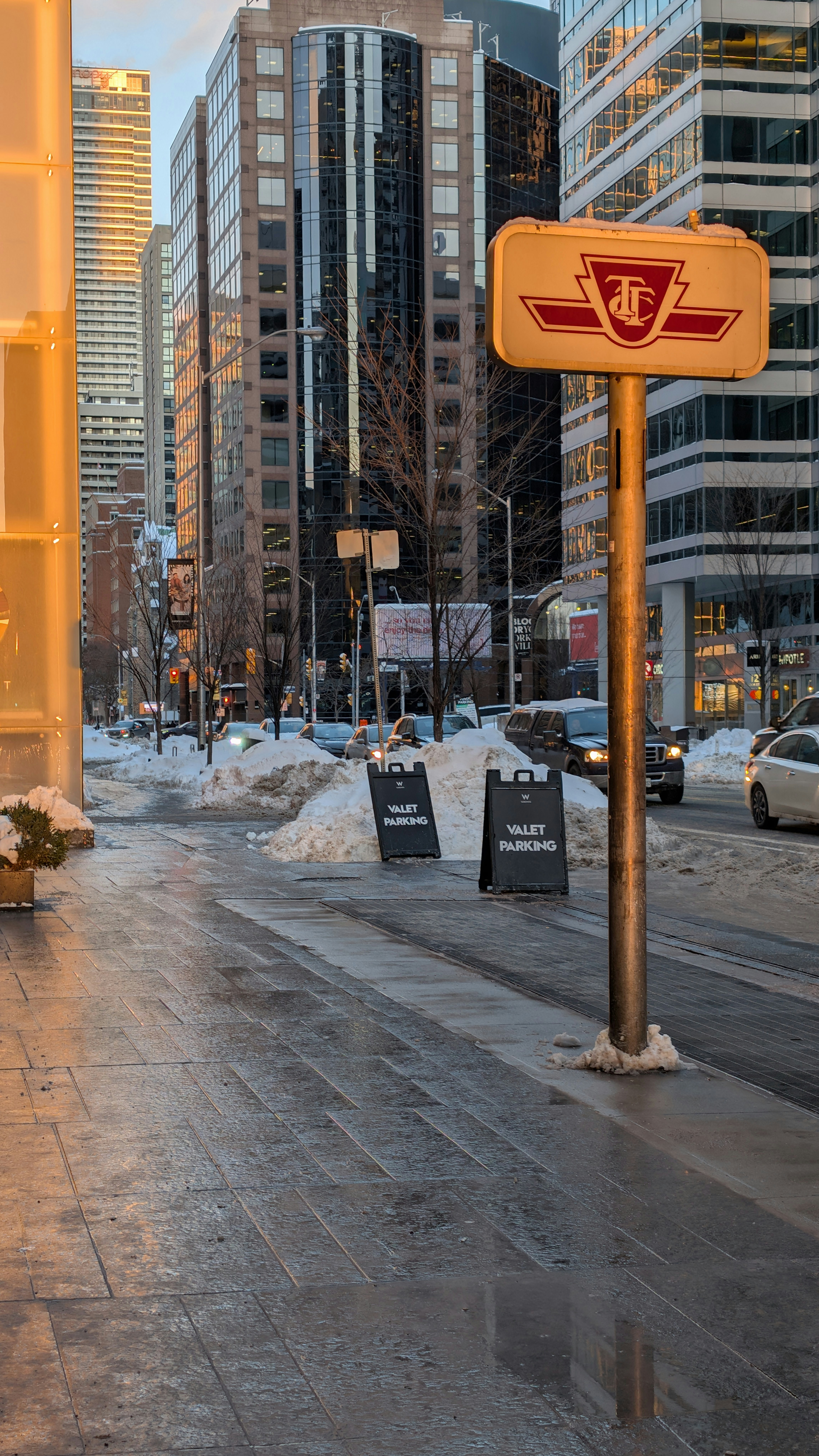 Yellow Logo Sign Anchors a Snowy Downtown Street Between Glass Towers