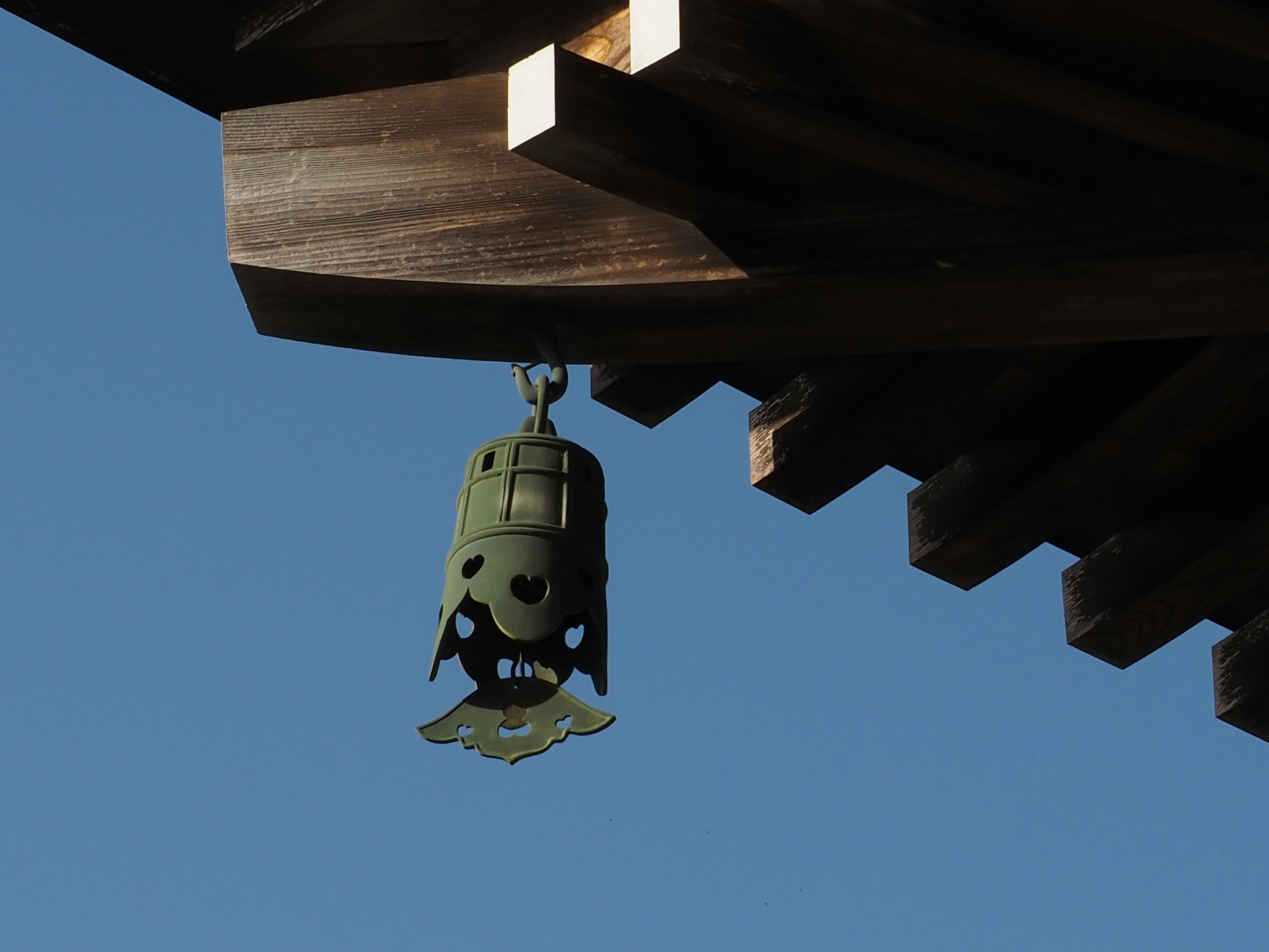 A bell hanging from a wooden structure with a sky background photo ...