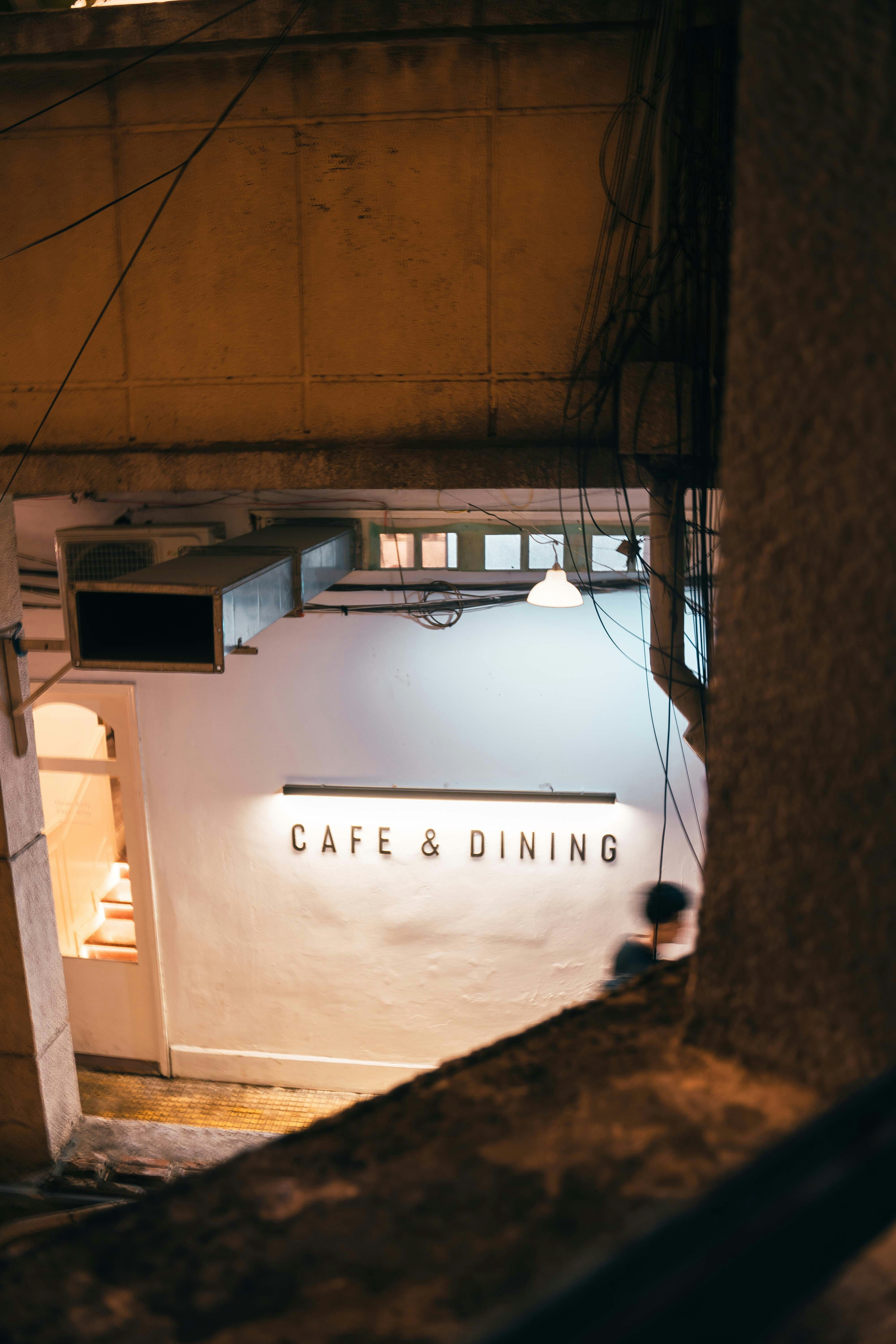 Signage for a cafe and dining area illuminated softly in a stairwell. The inviting atmosphere hints at a cozy dining experience.
