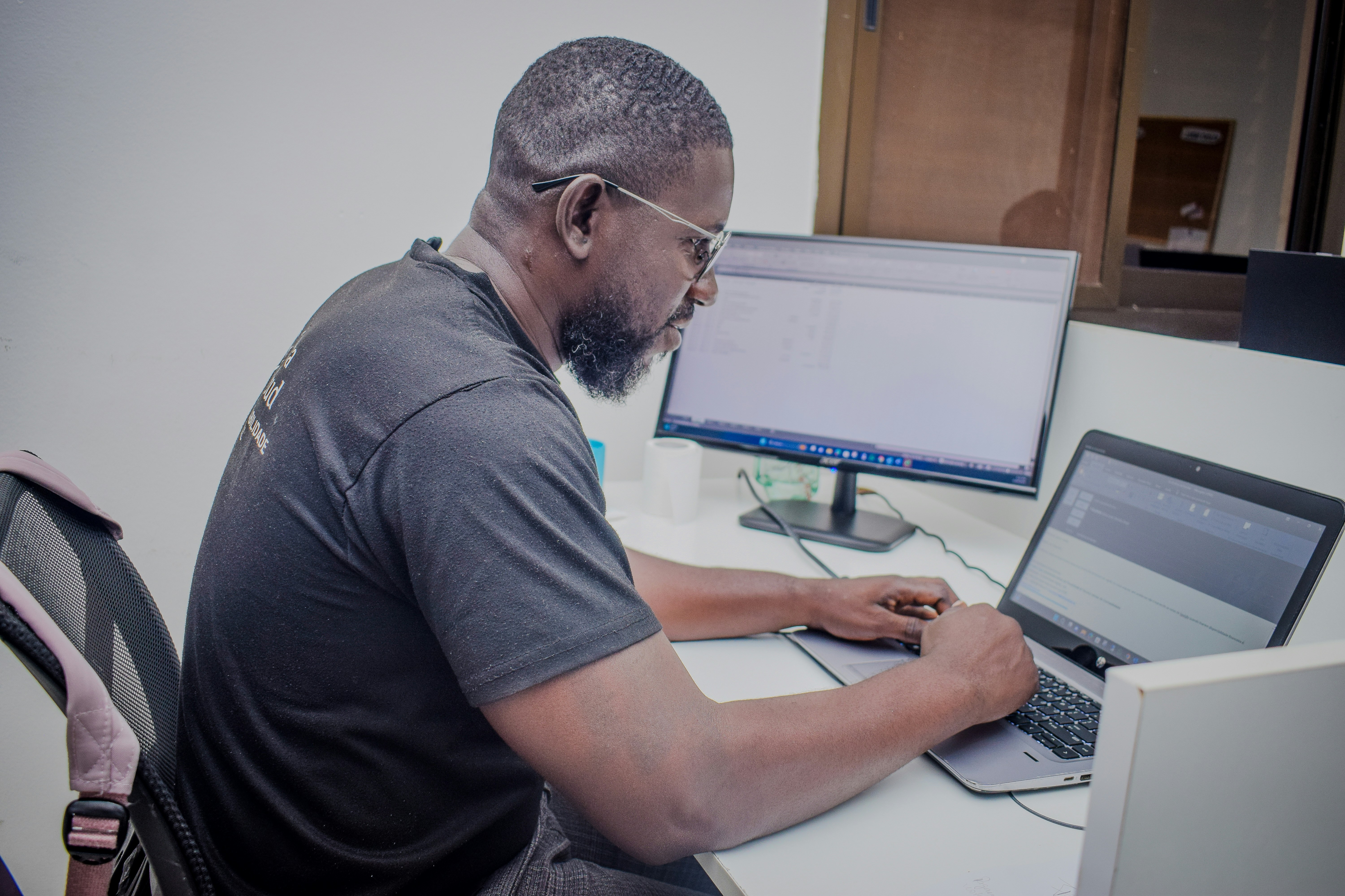 A man sitting at a desk using a laptop computer photo – Free Computer ...