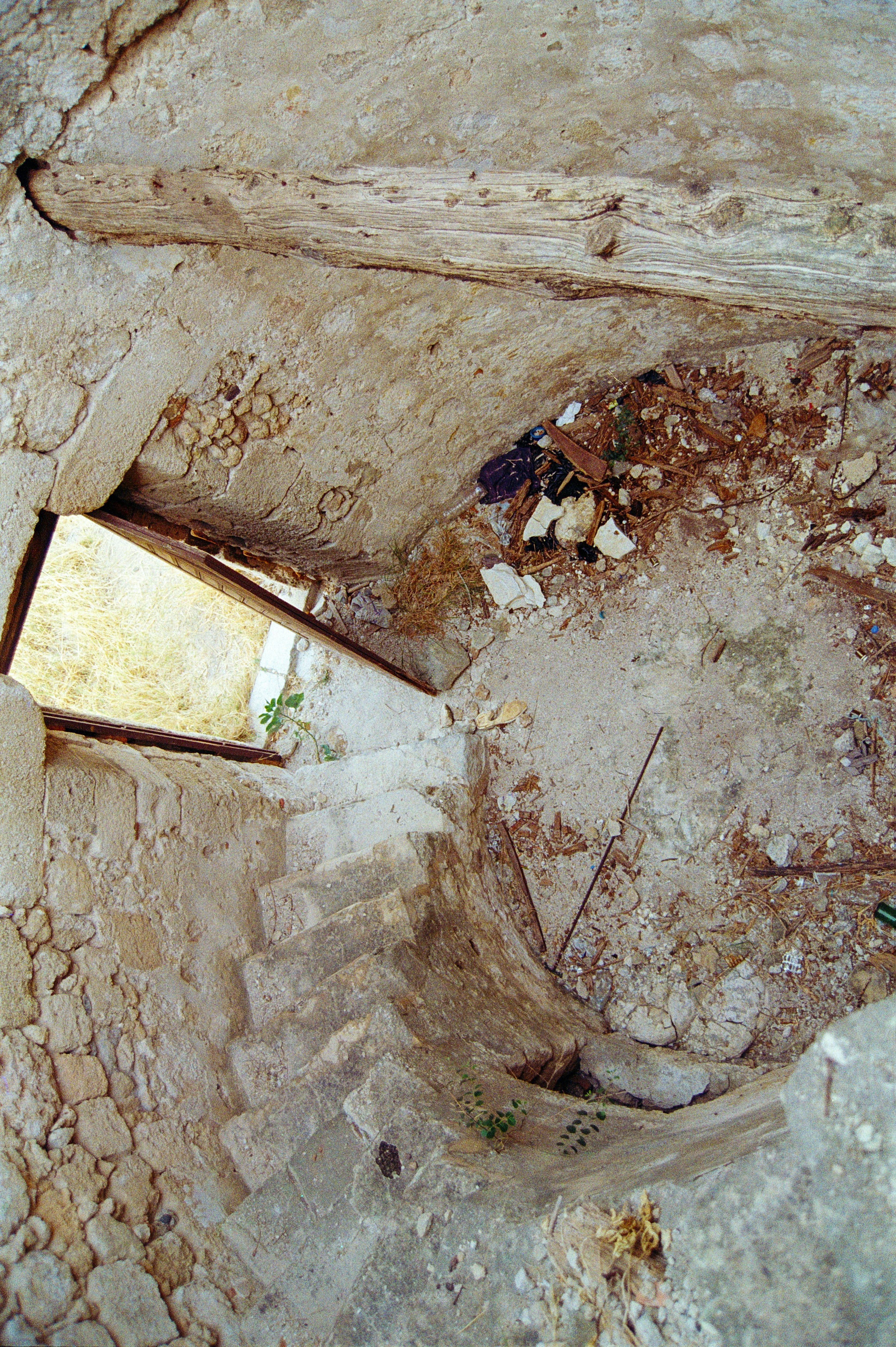 Ancient Spiral Descent: Sunlit Ruins Framing a Weathered Circular Stair