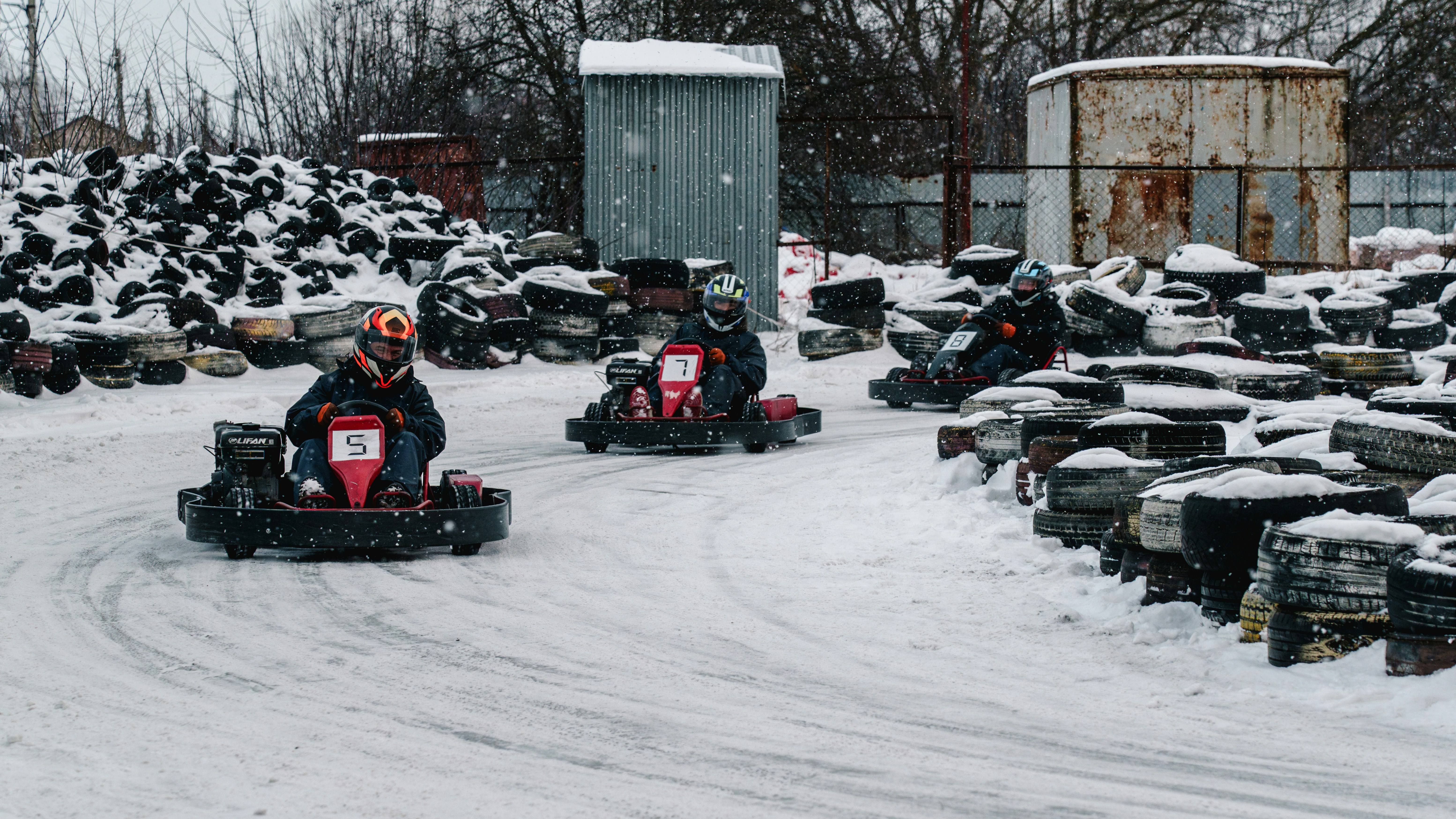 A group of people riding snowmobiles down a snow covered road photo ...