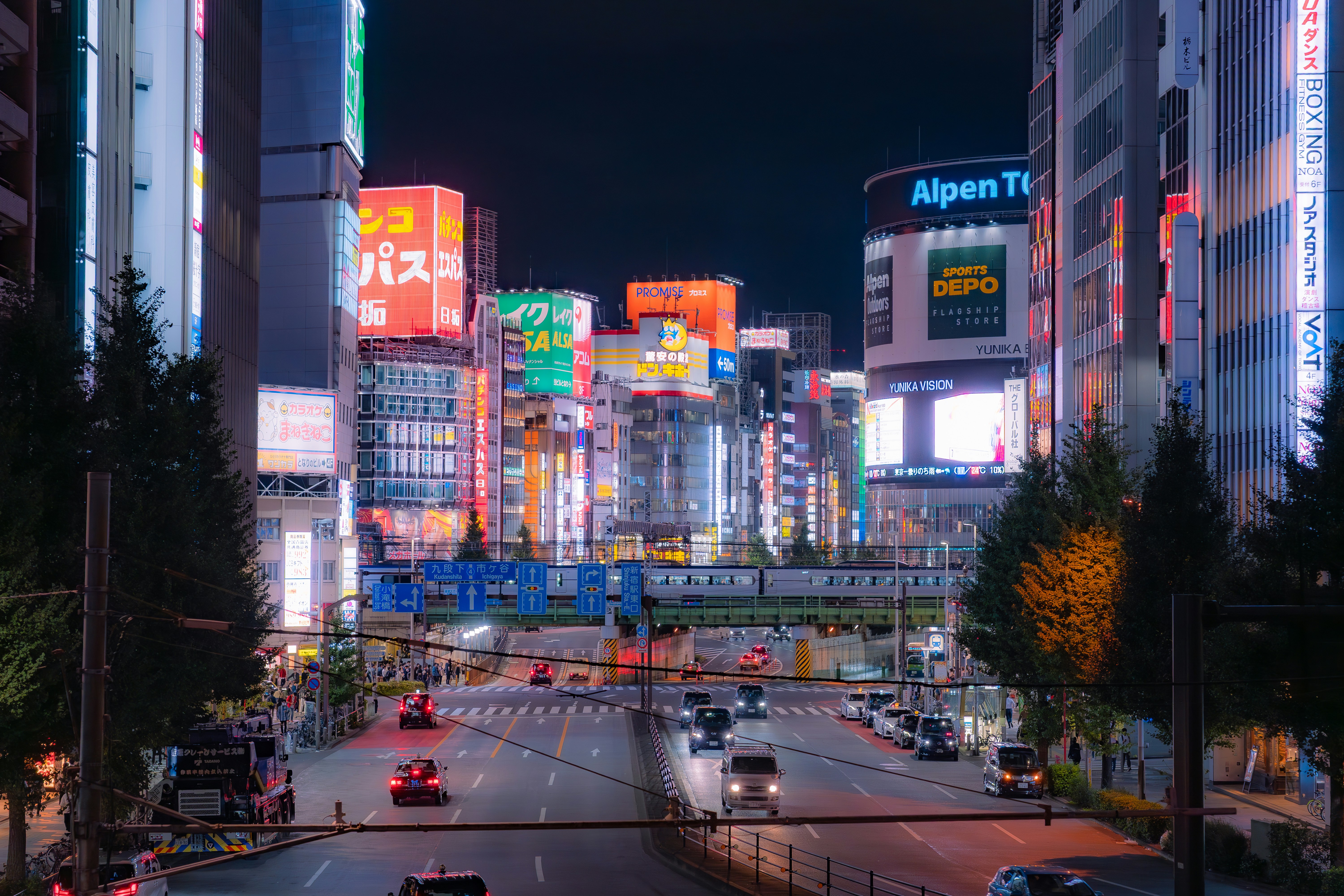 Vibrant cityscape of Shinjuku at night with colorful neon signs and bustling traffic.