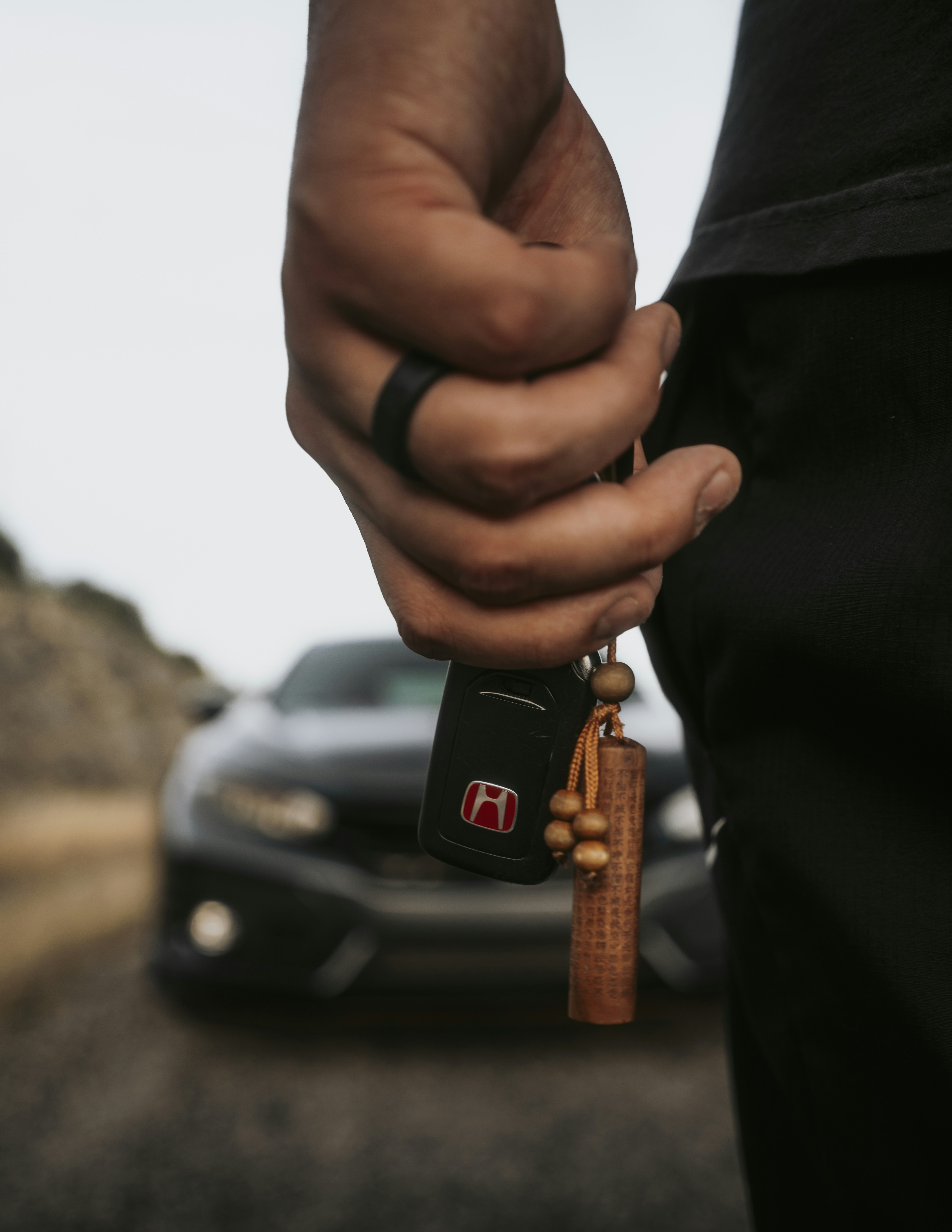 A person holding a car key with a car in the background photo – Free ...
