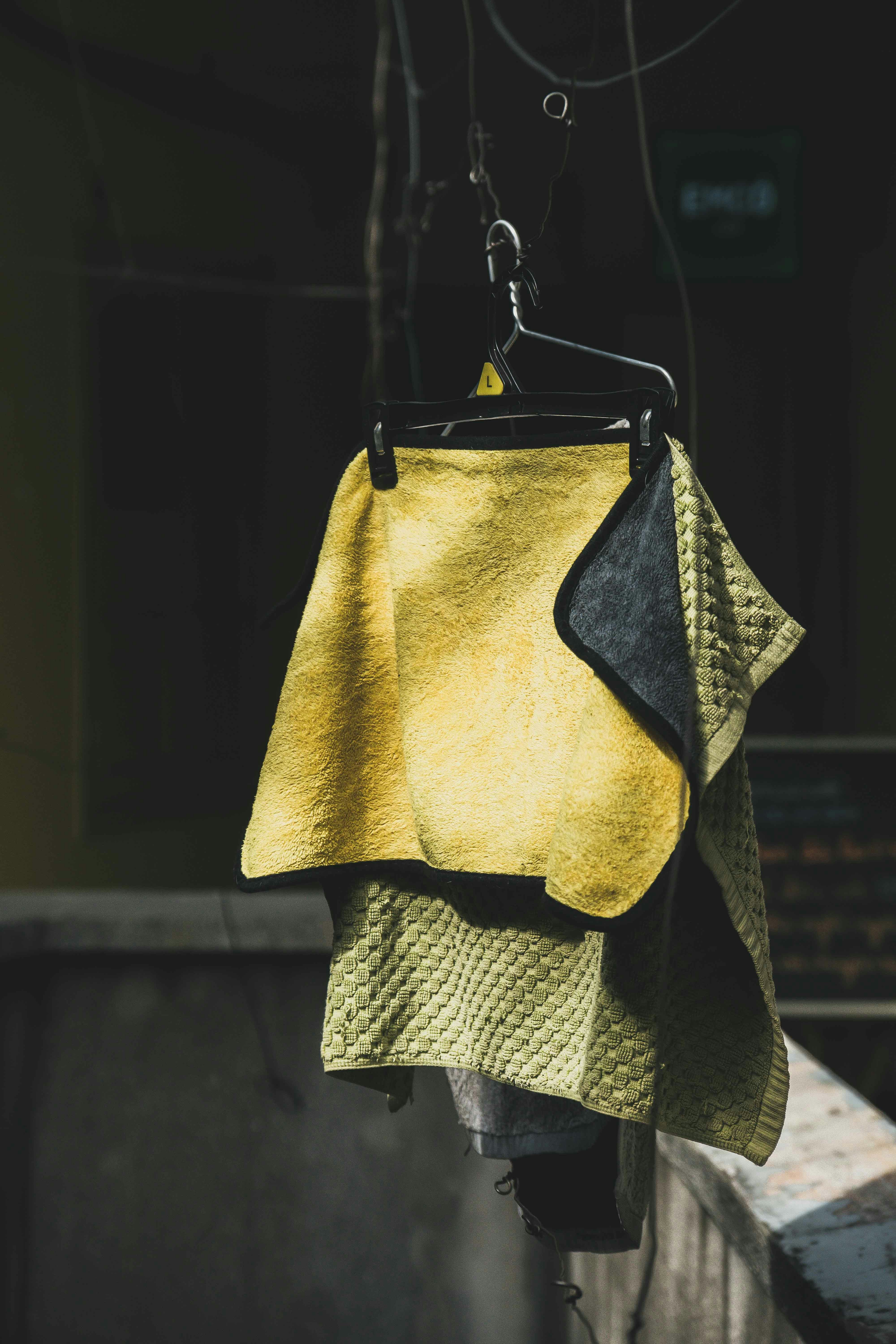 Industrial Hue: A Bright Yellow Towel Draped Over a Hanging Hook in a Shadowy Workshop