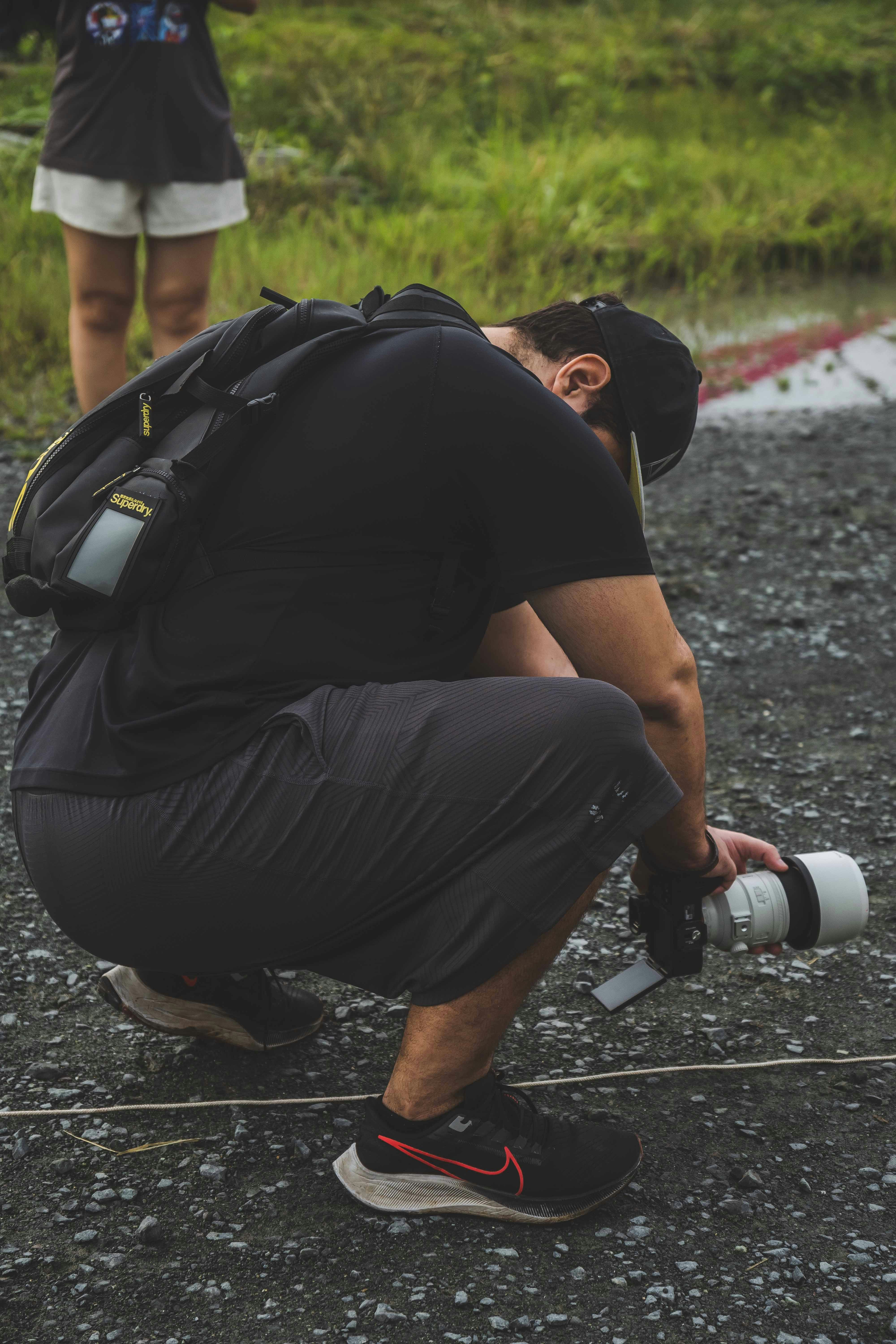Ground-Level Focus: A Photographer Calibrates a White Telephoto on a Gravel Shoot