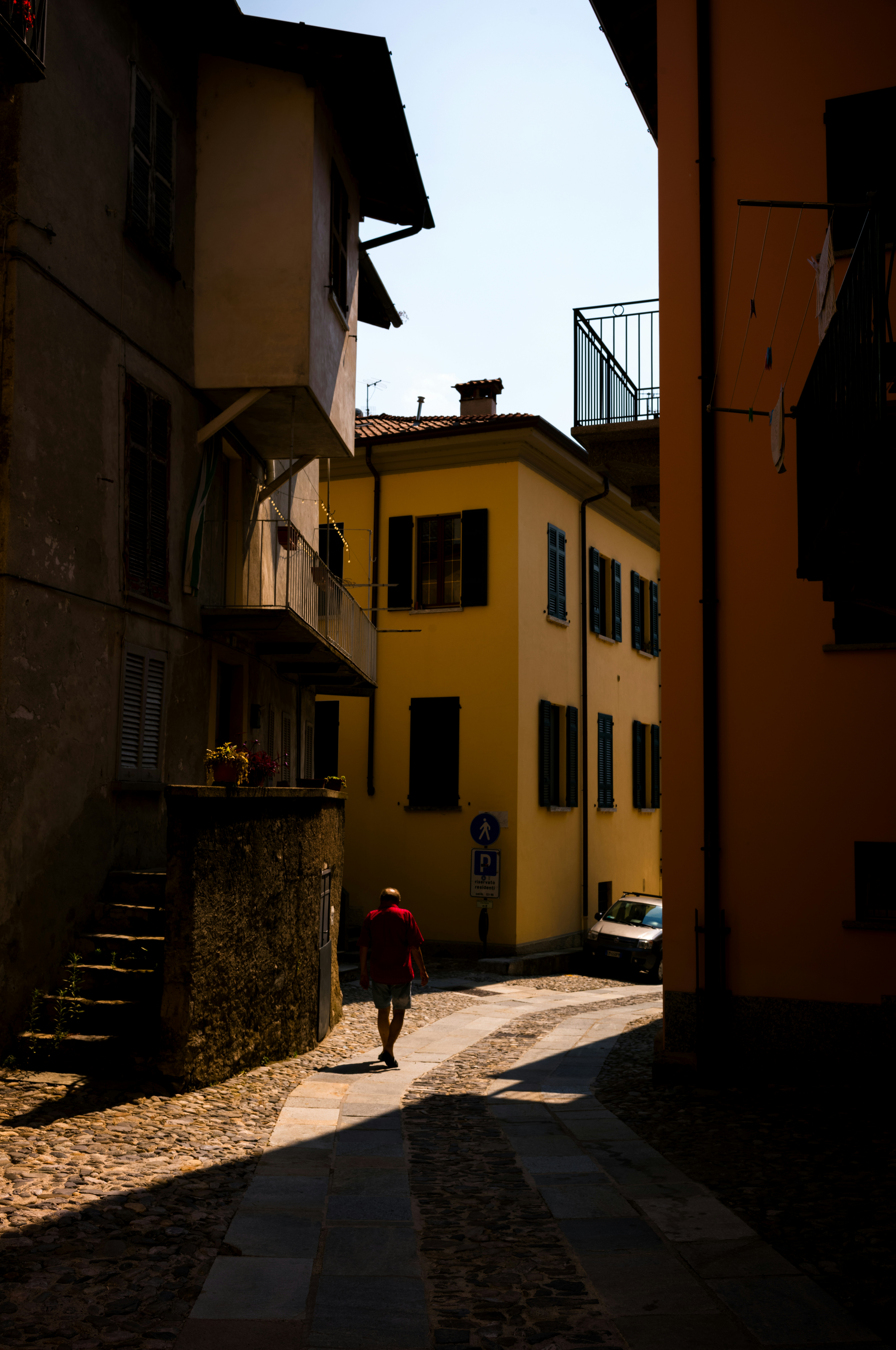 Red Traveler in a Sunlit Alley Between Yellow Facades