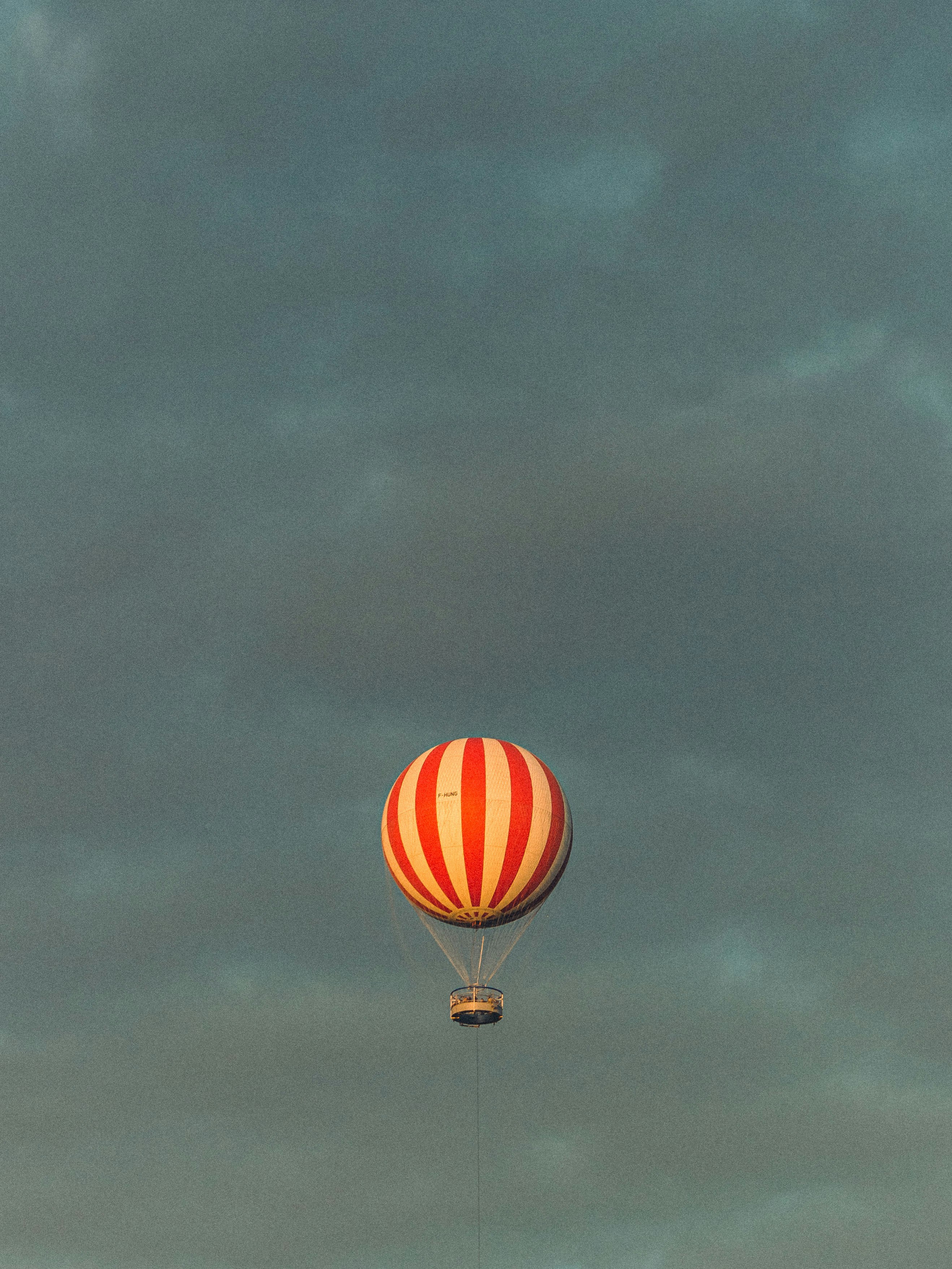 A Lone Red-and-White Balloon Drifts Beneath a Moody Sky