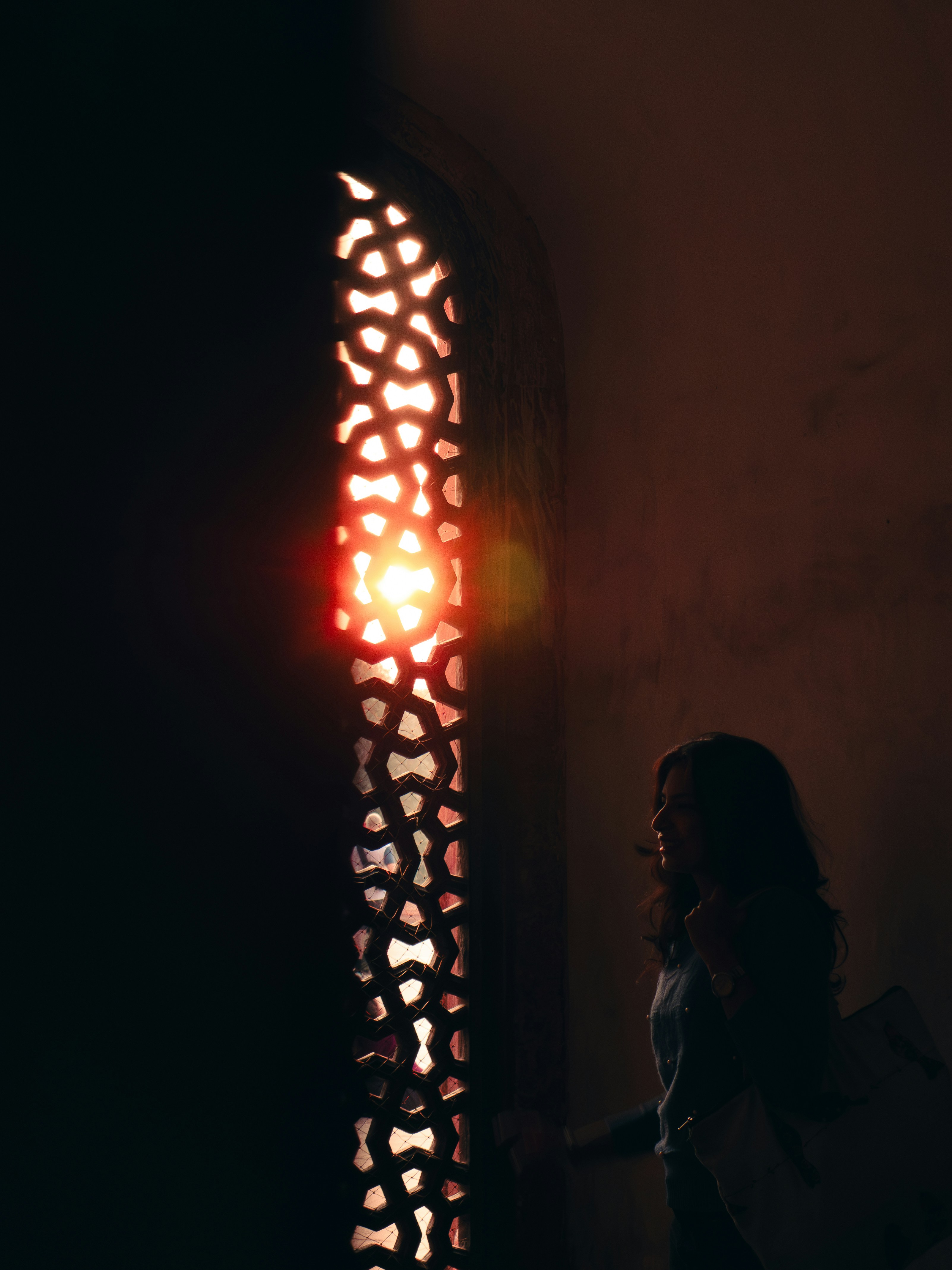 Crimson Light Through a Carved Lattice: A Quiet Figure by the Doorway