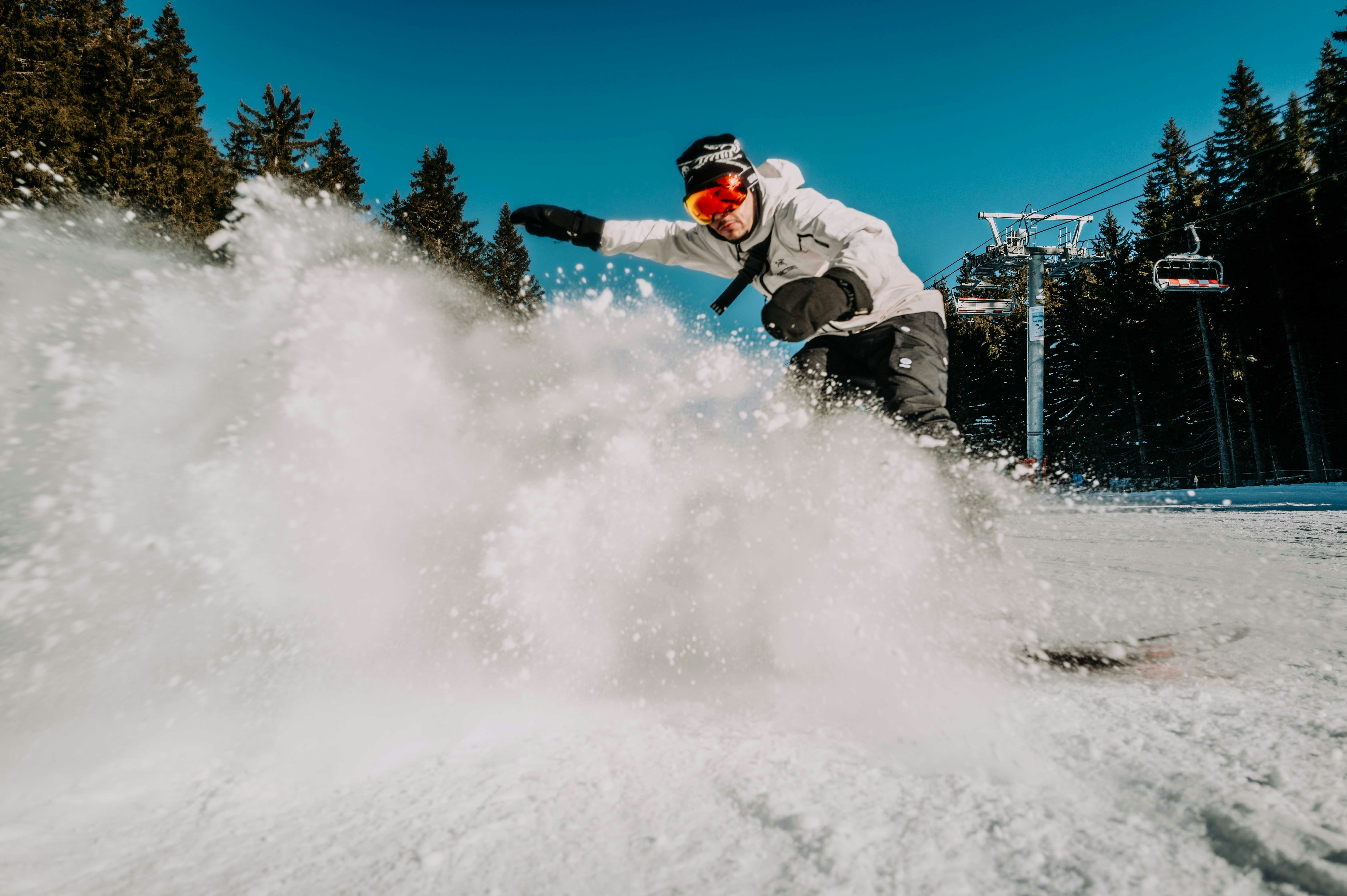 A man riding a snowboard down the side of a snow covered slope photo ...