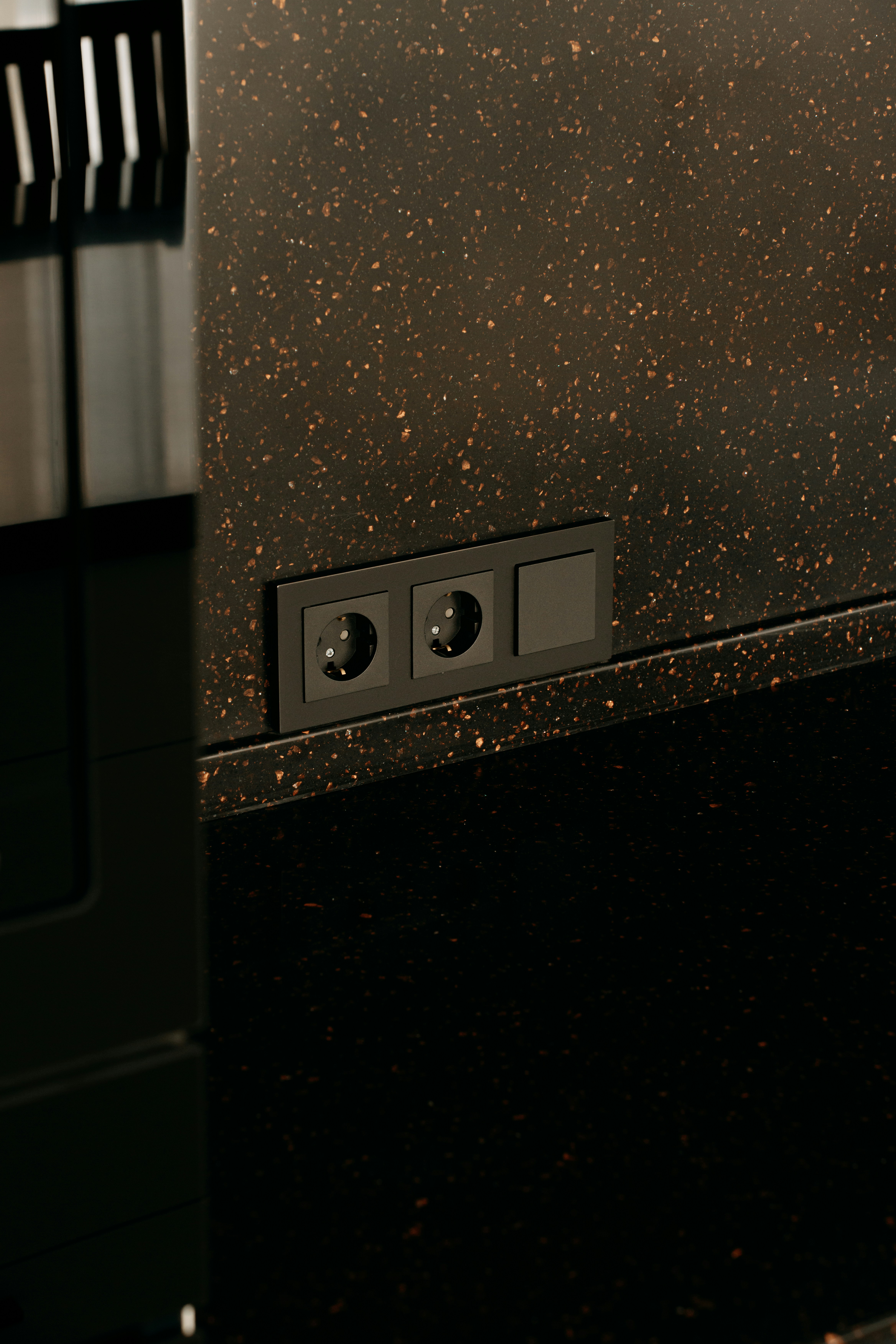 Sleek electrical outlets set against a textured dark surface, showcasing a blend of form and function in contemporary design.