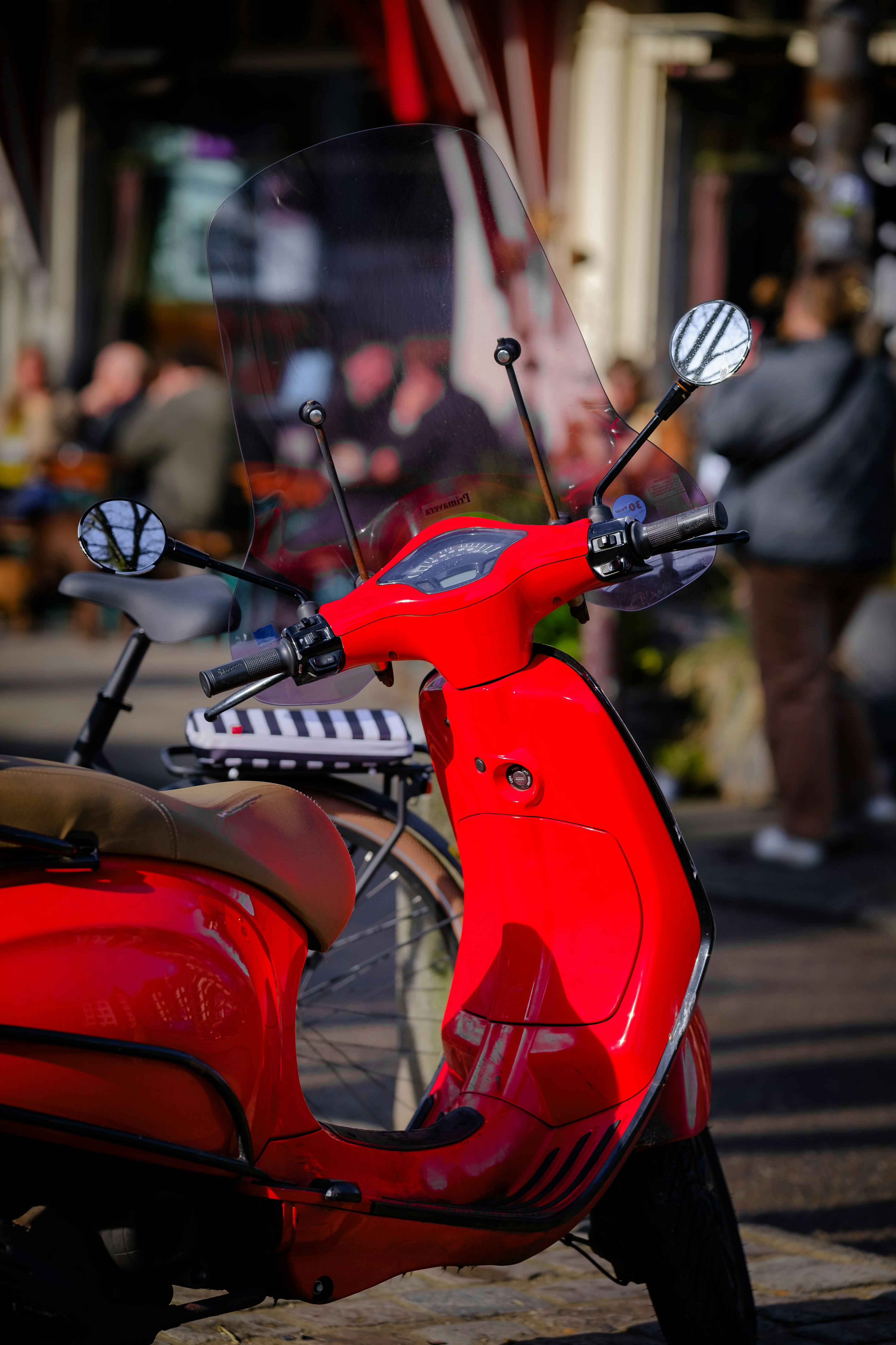 Flame-red Vespa in Focus: Street Scene with Tilted Windshield