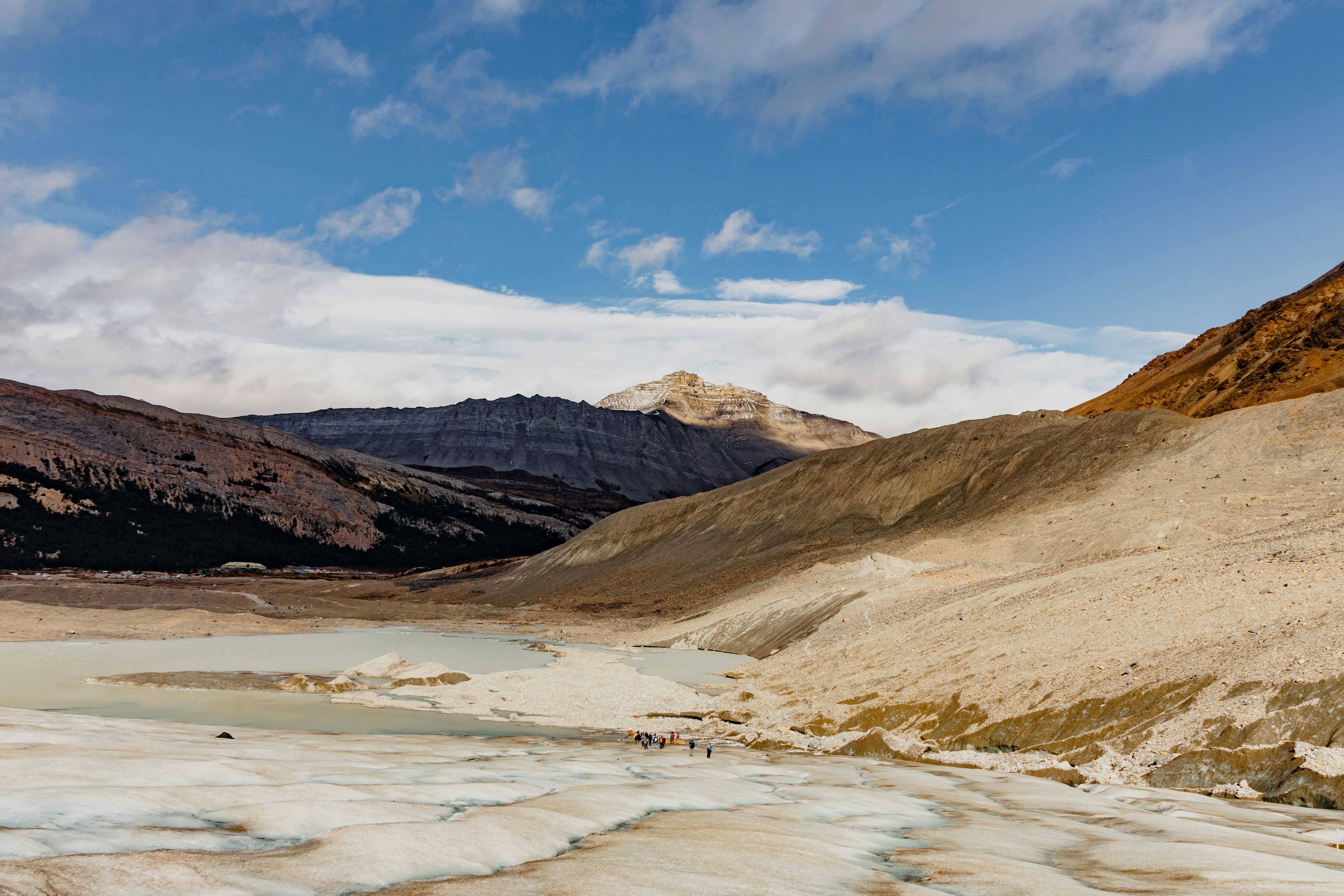 Expansive glacier with hikers in a rugged mountain landscape under a vivid blue sky.