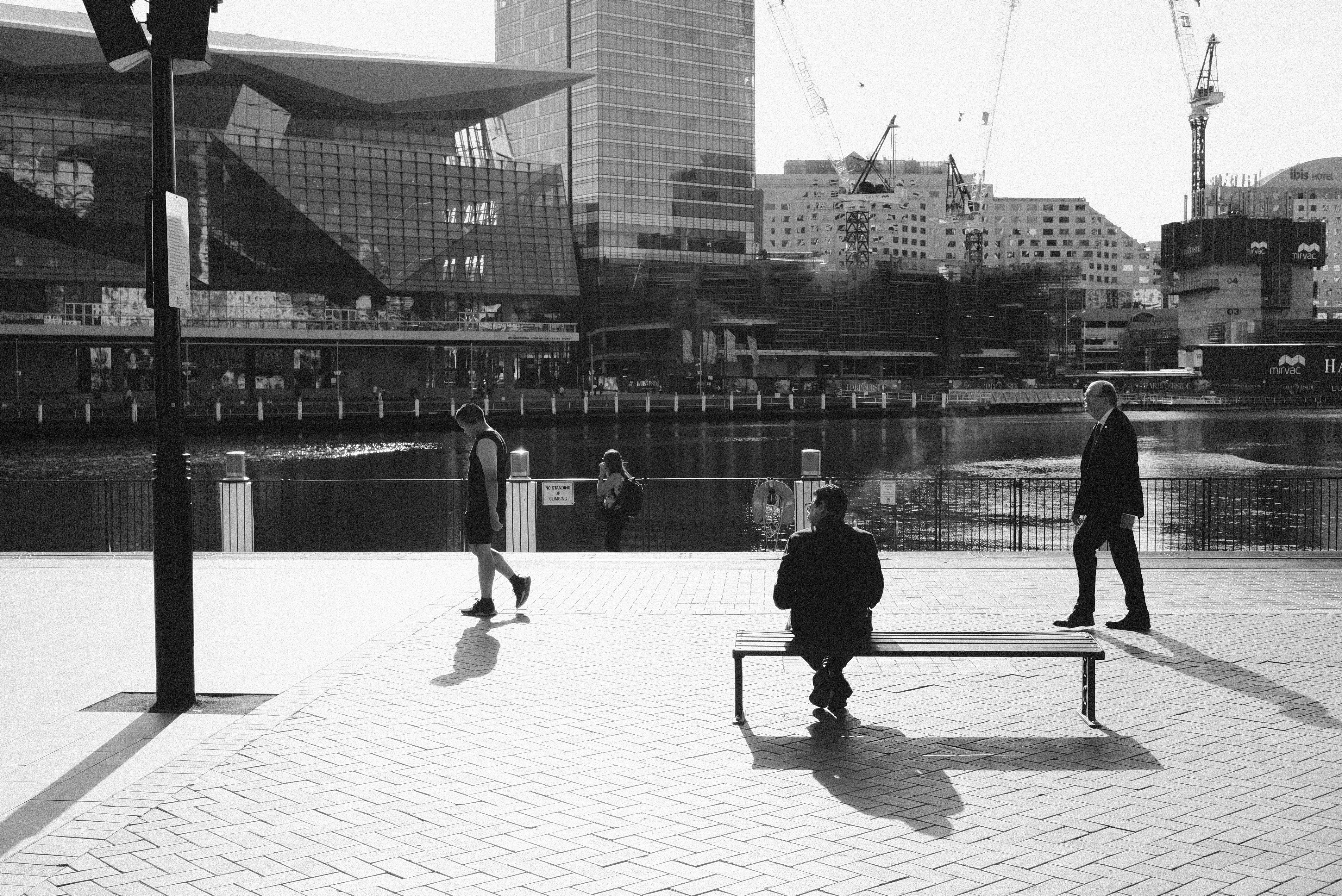 Riverside Quiet: A Benched Figure Amid Urban Shadows