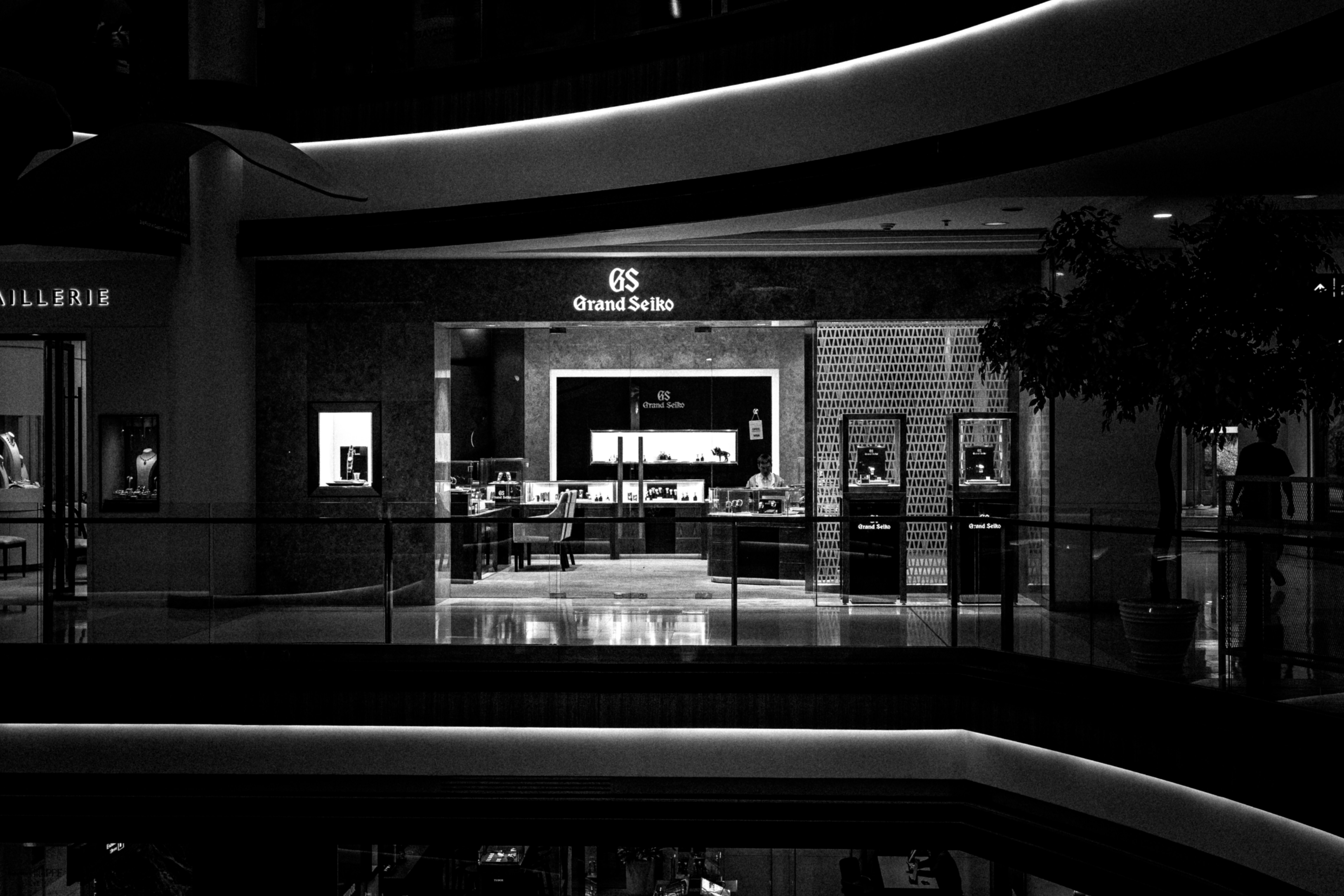 Black and white view of a luxury boutique storefront in a dimly lit shopping mall.