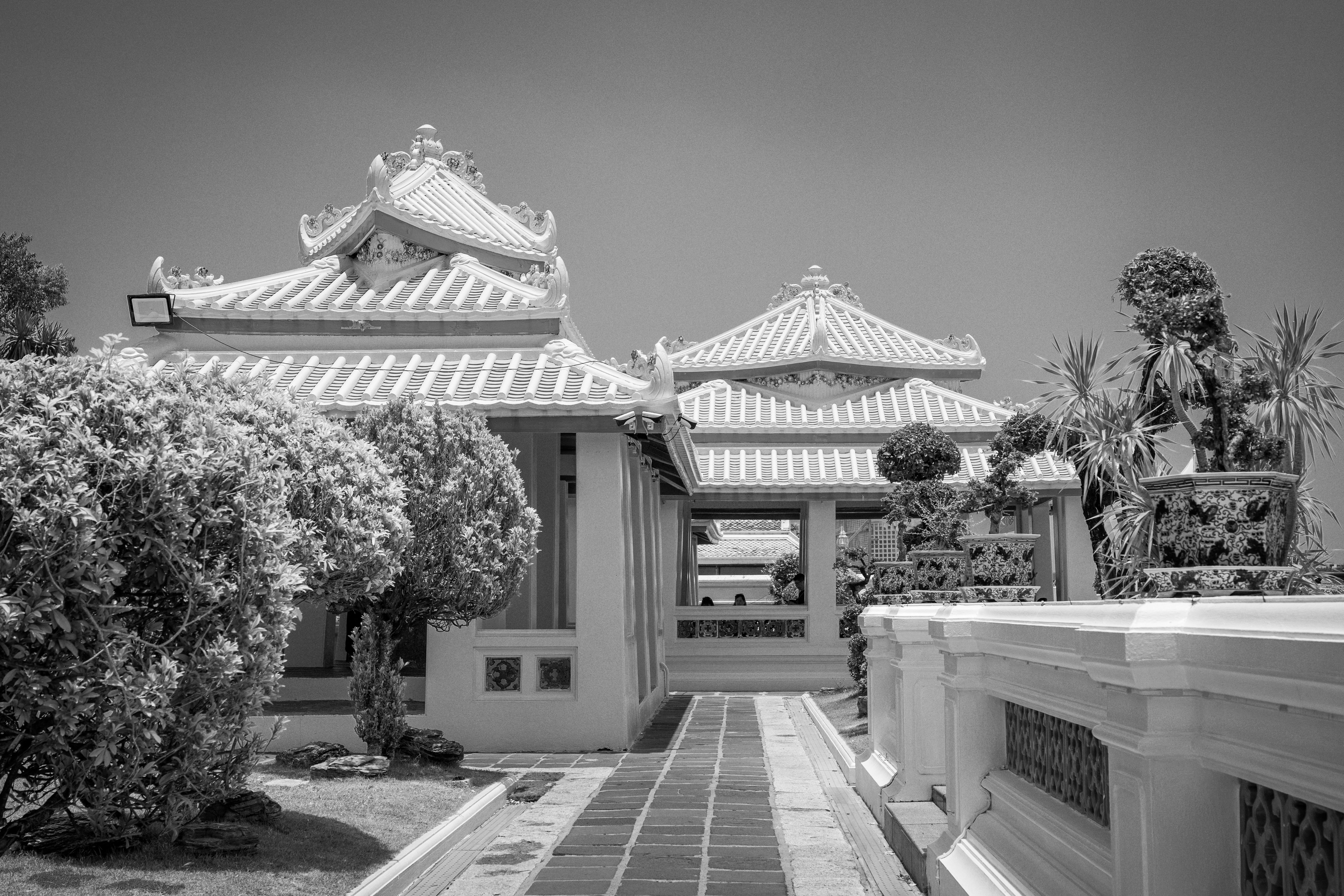 Traditional Asian architecture with ornate rooftops and manicured gardens under a clear sky.