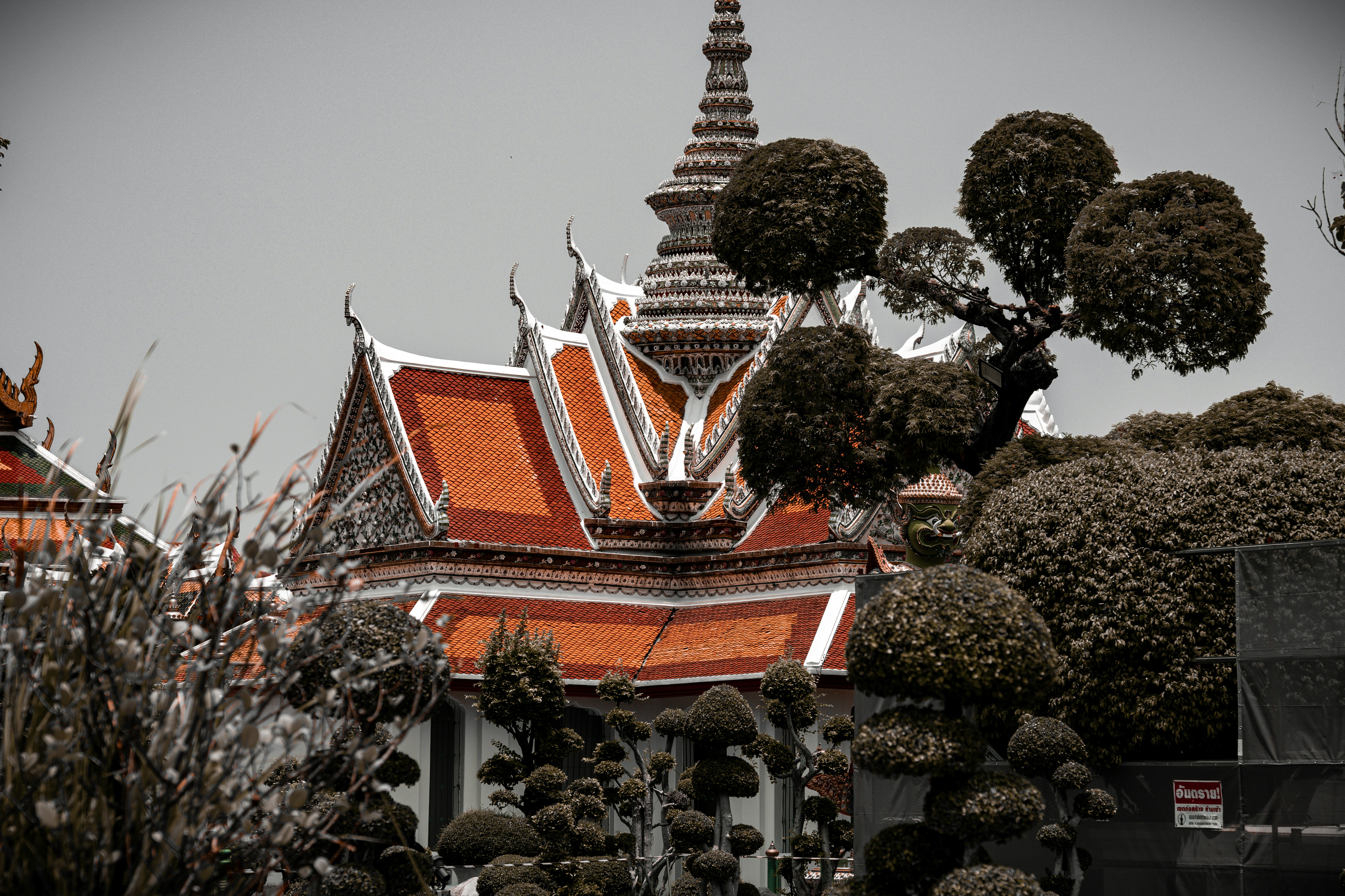 Ornate Thai Temple Rooflines Rise Through Sculpted Foliage