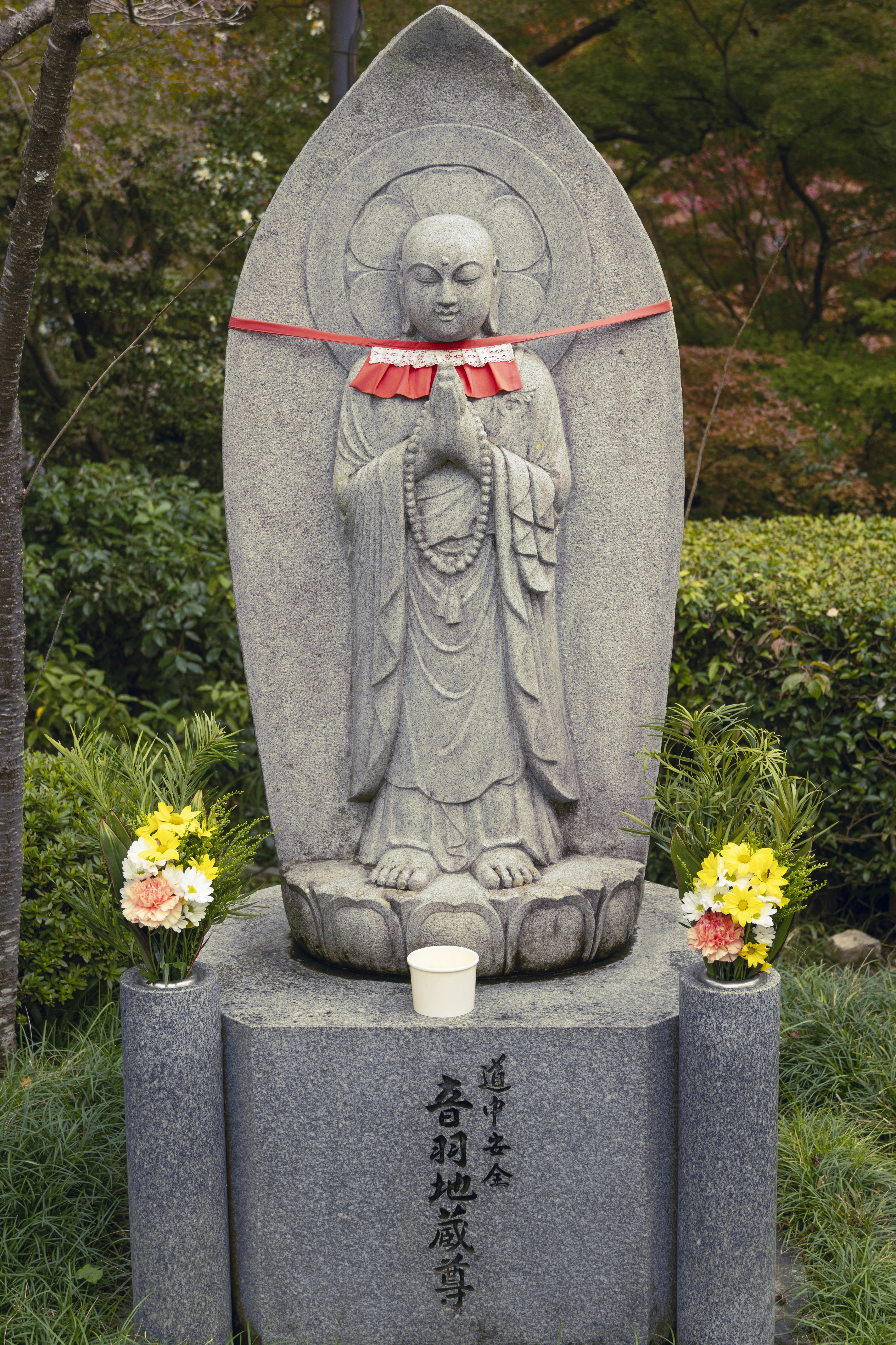 Red Ribbon Grace: A Buddha Statue in a Quiet Garden Shrine